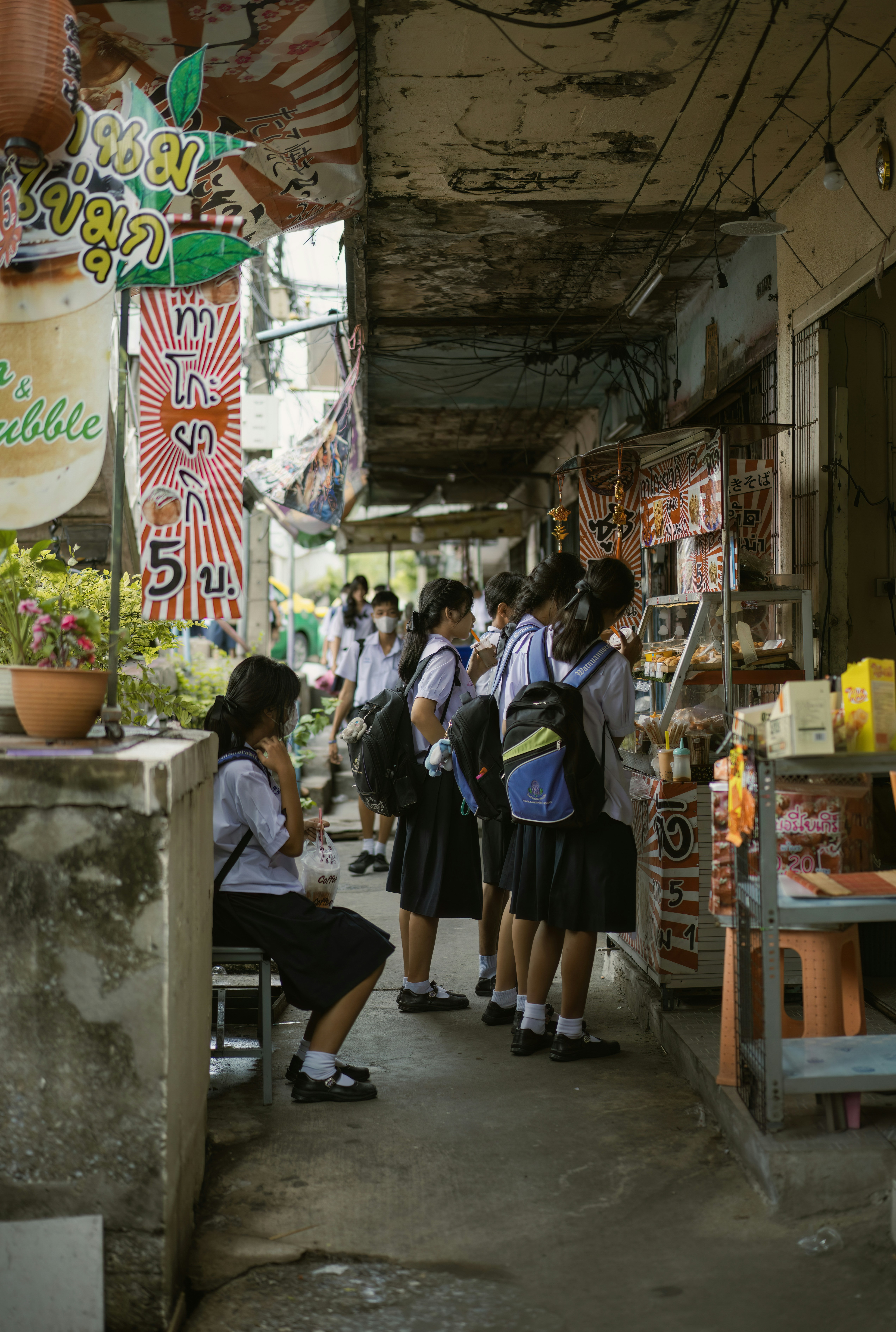 Narrow Market Corridor: Uniformed Students Amid Colorful Signboards