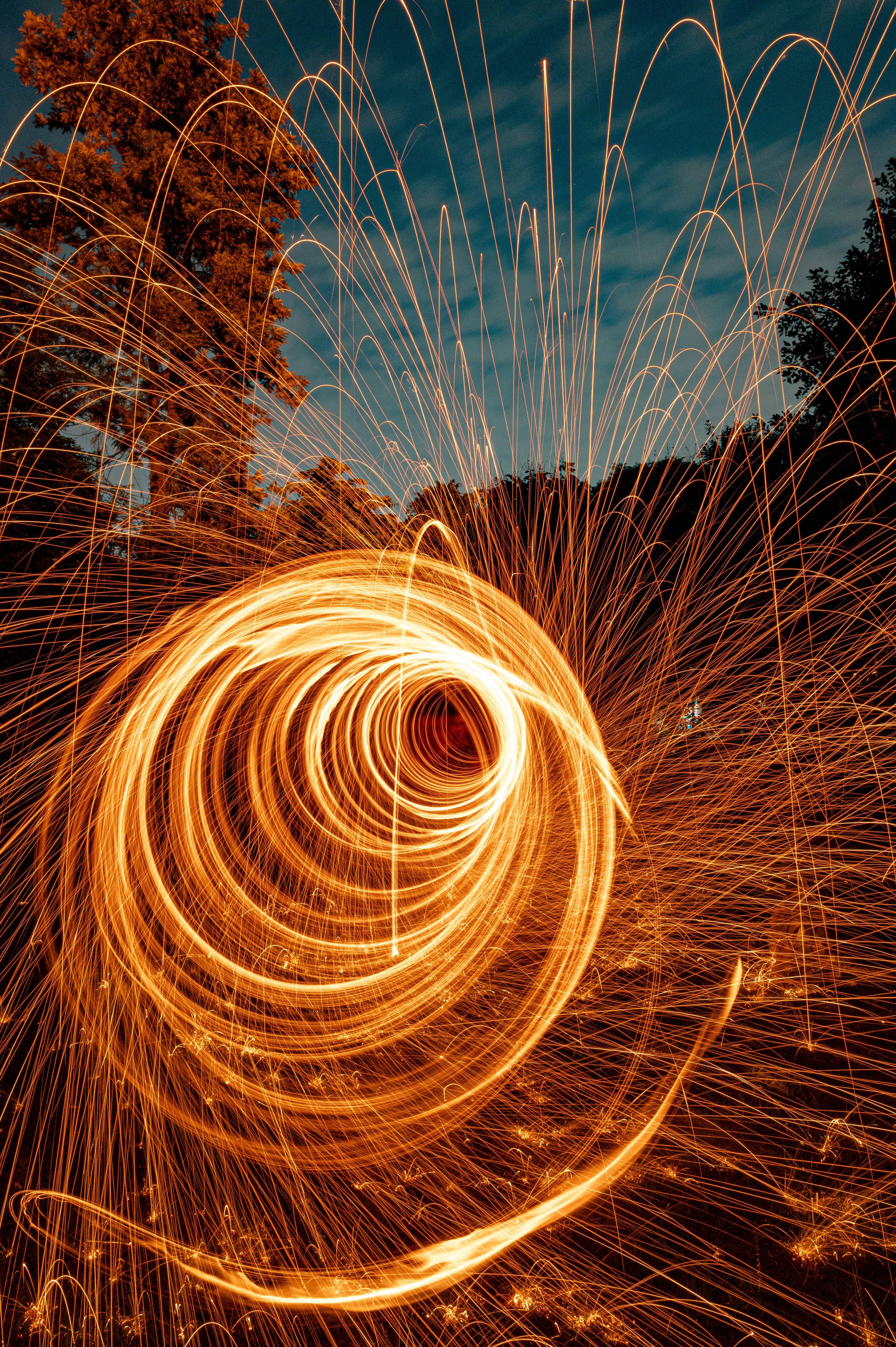 A firework spinning in the air with trees in the background photo ...