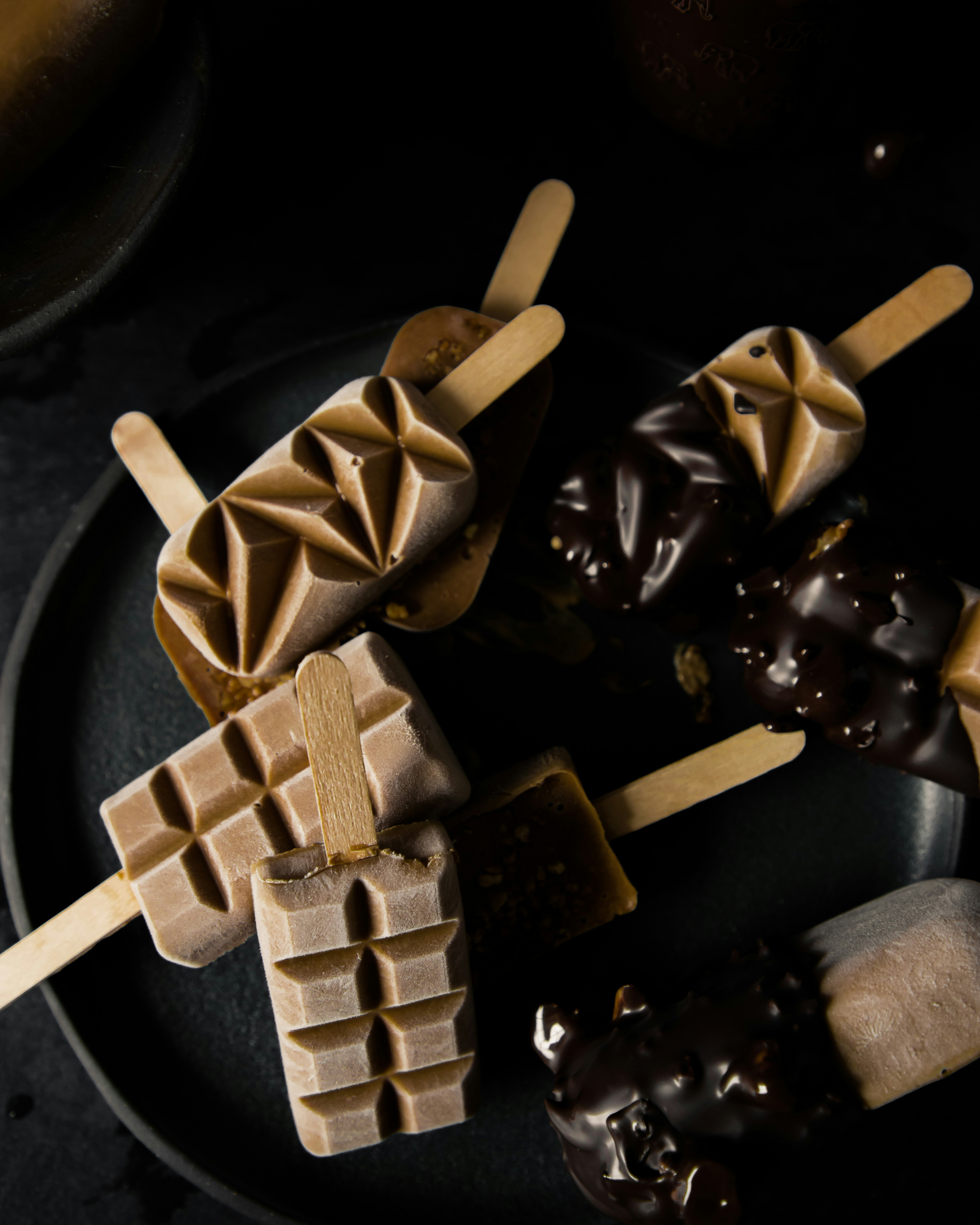 Sticks of Cocoa Art: Assorted Chocolate Pops on a Dark Plate