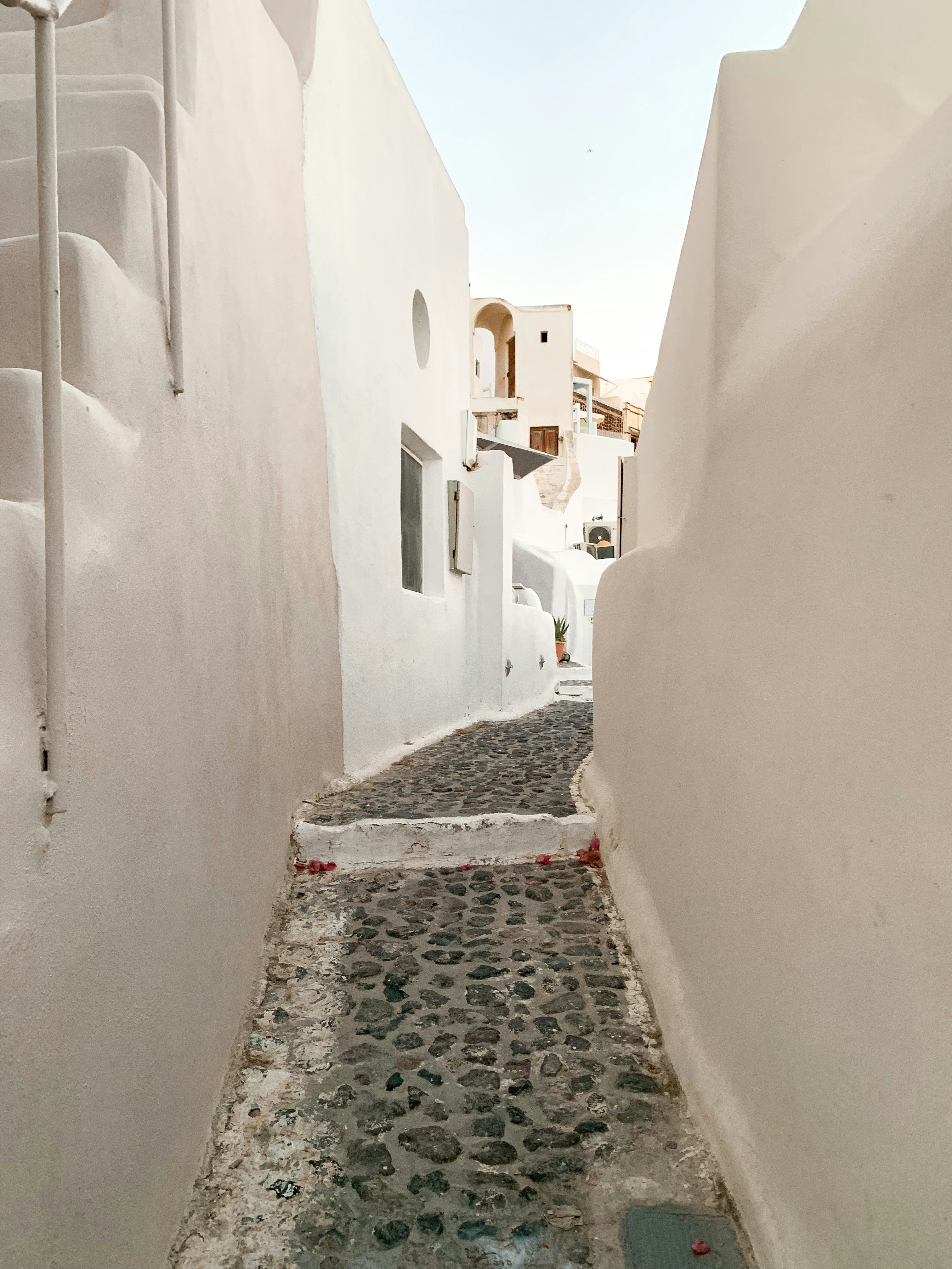 A narrow alley way with white walls and cobblestones photo – Free Oia ...