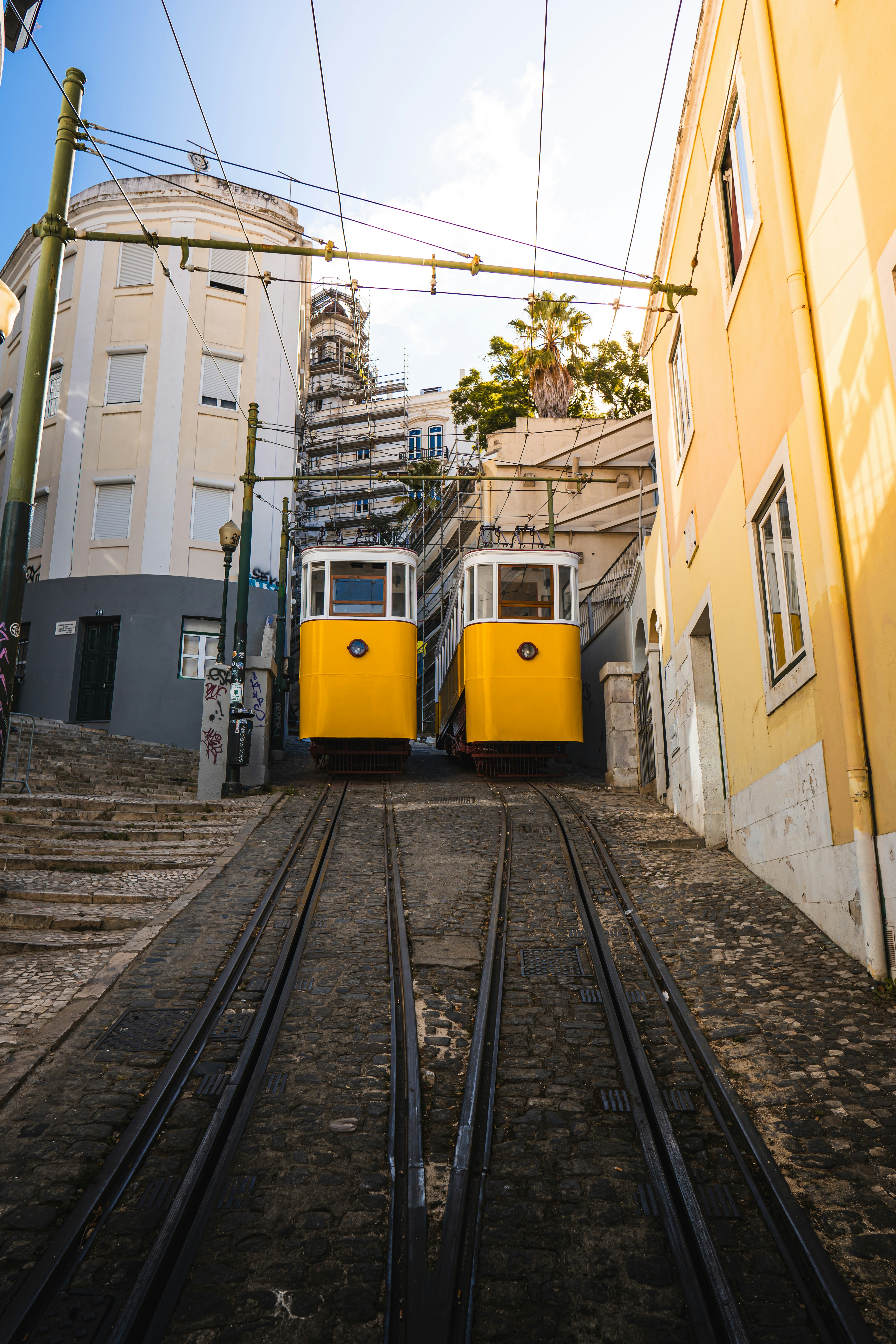 Twin Yellow Trams Climb a Cobblestone Urban Slope