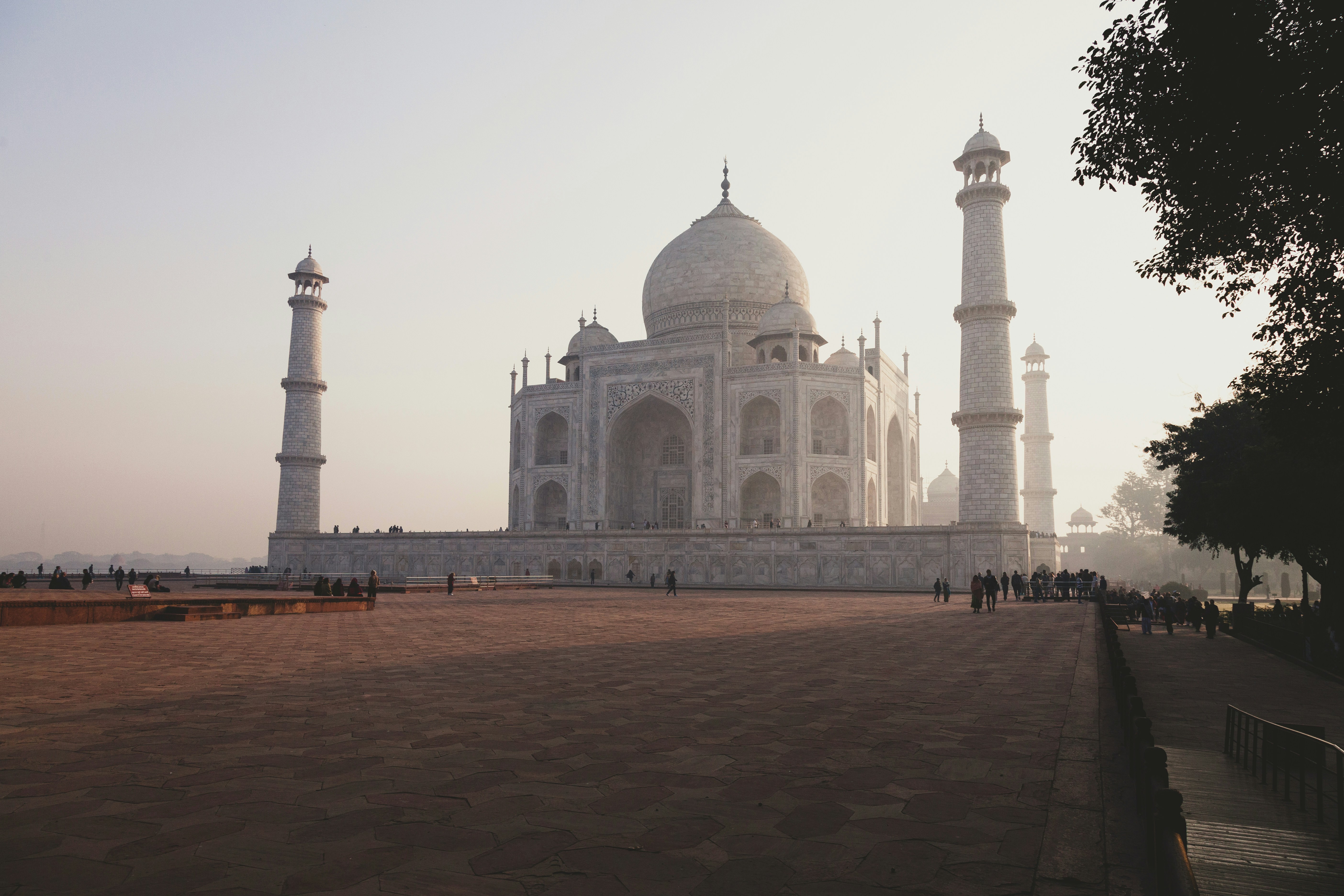 This captivating image of the Taj Mahal captures the iconic monument enveloped in a soft morning haze, creating a serene and mystical atmosphere. The balanced composition highlights the majestic domes and minarets, with soft sunlight casting gentle shadows on the pristine white marble. The muted colors and subtle contrast emphasize the tranquility and timeless beauty of this architectural masterpiece.