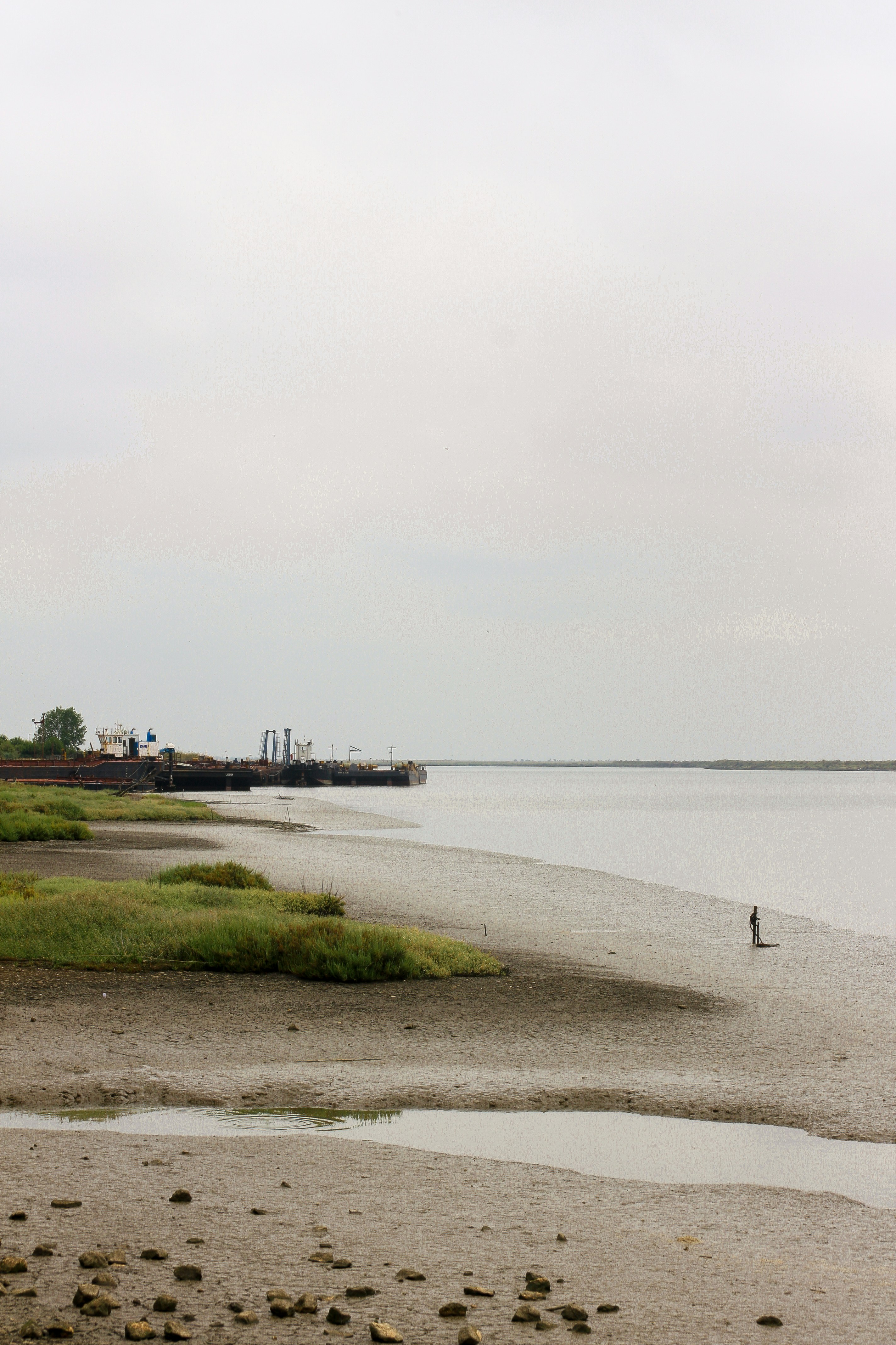 Mudflats and the Distant Barque: A Solitary Figure Beneath Expansive Skies