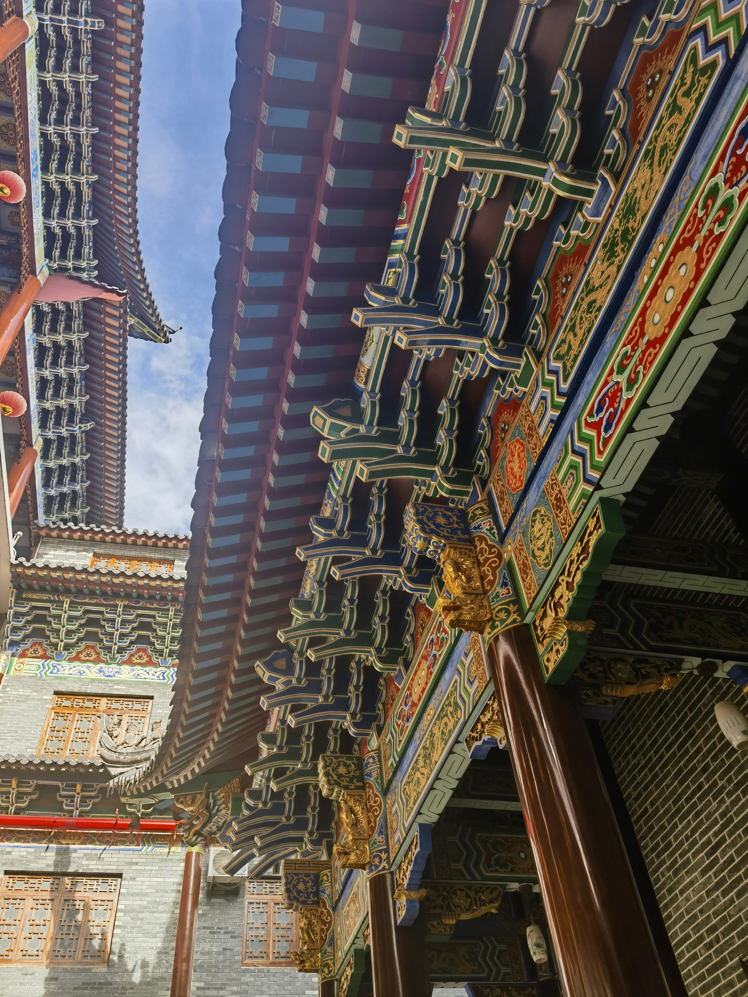 Intricate wooden beams and colorful eaves of traditional architecture under a bright sky, showcasing cultural artistry.