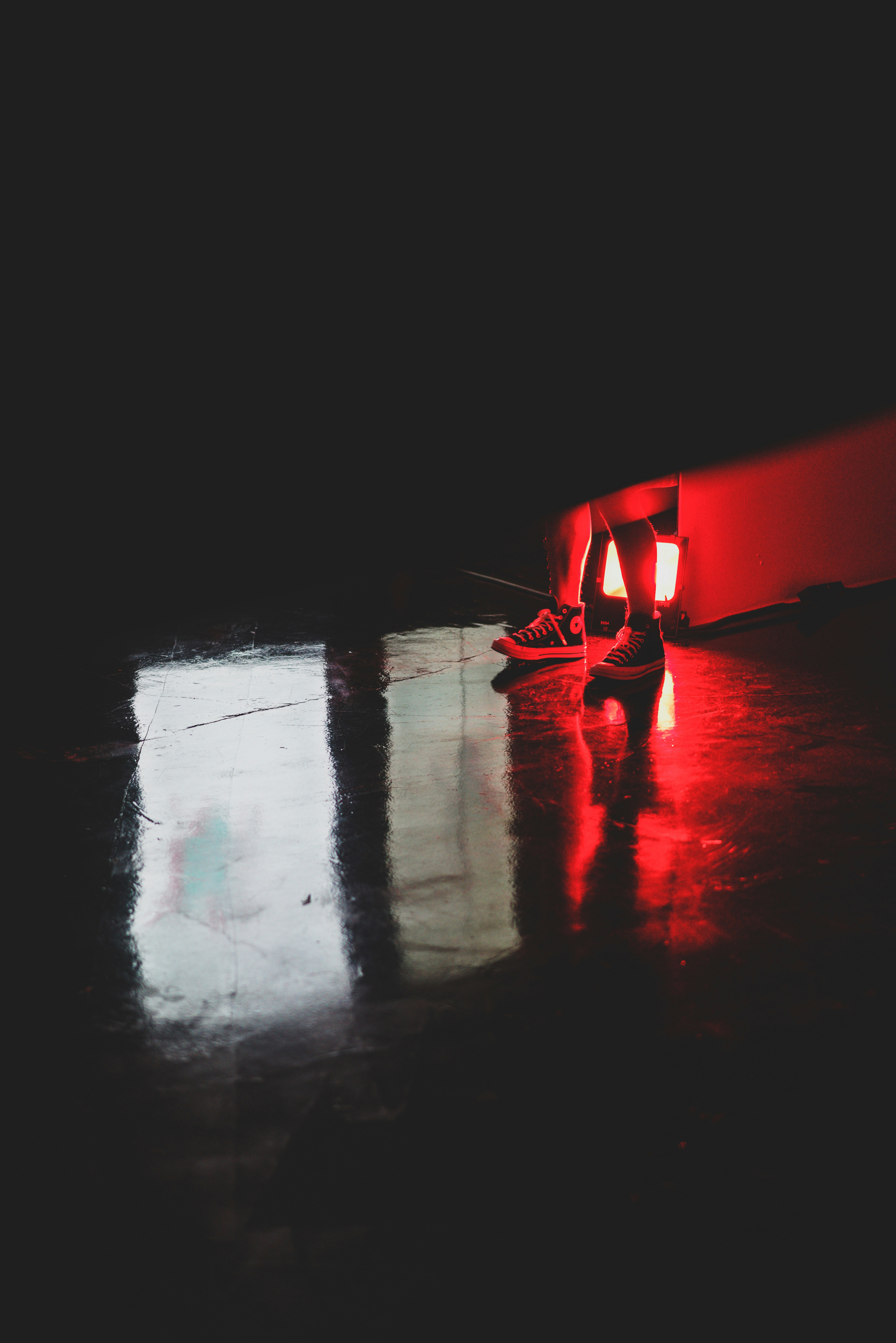Red Neon Footlights: Sneakers Rest by a Dark Corridor