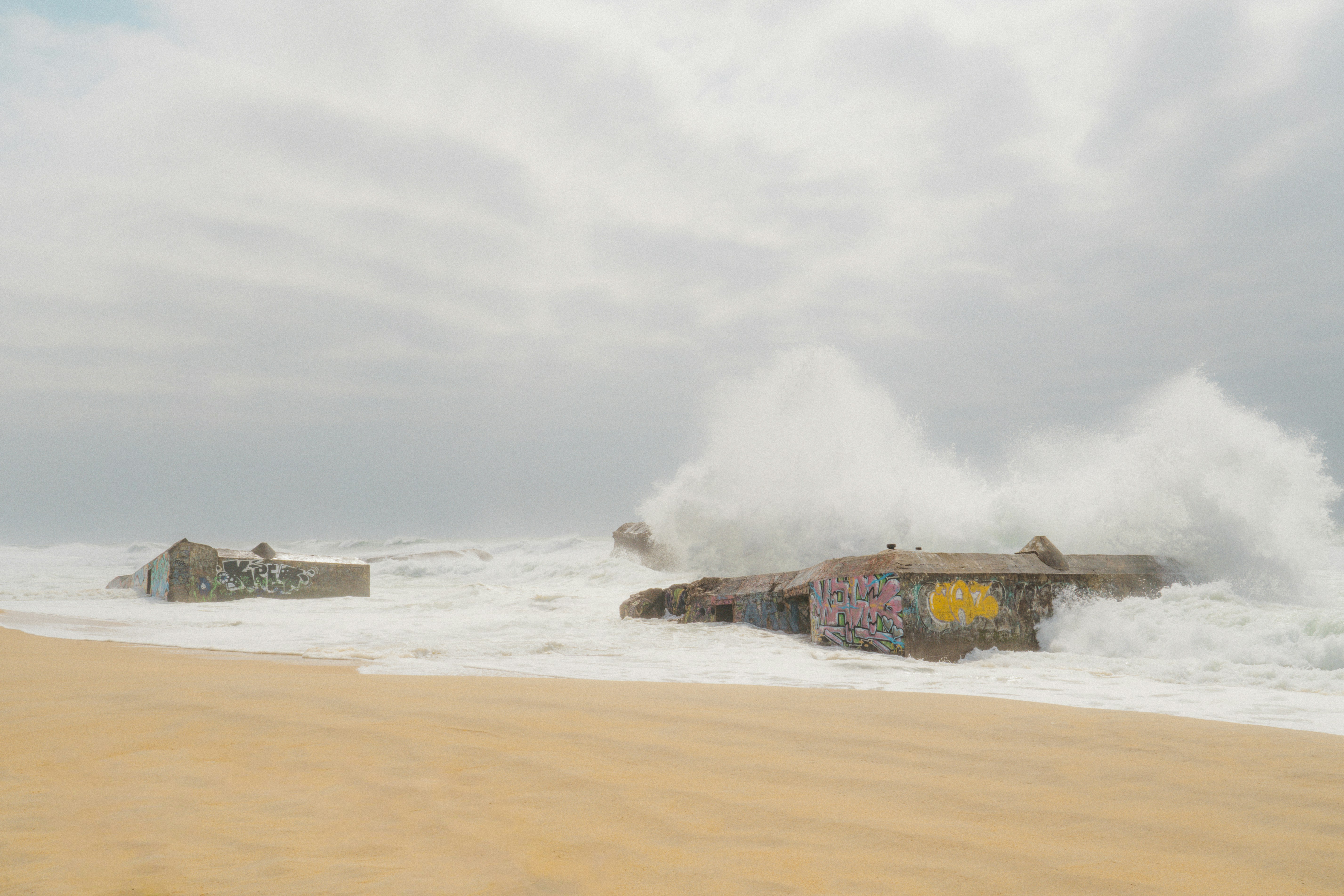 A large wave crashes over a building on the beach photo – Free ...