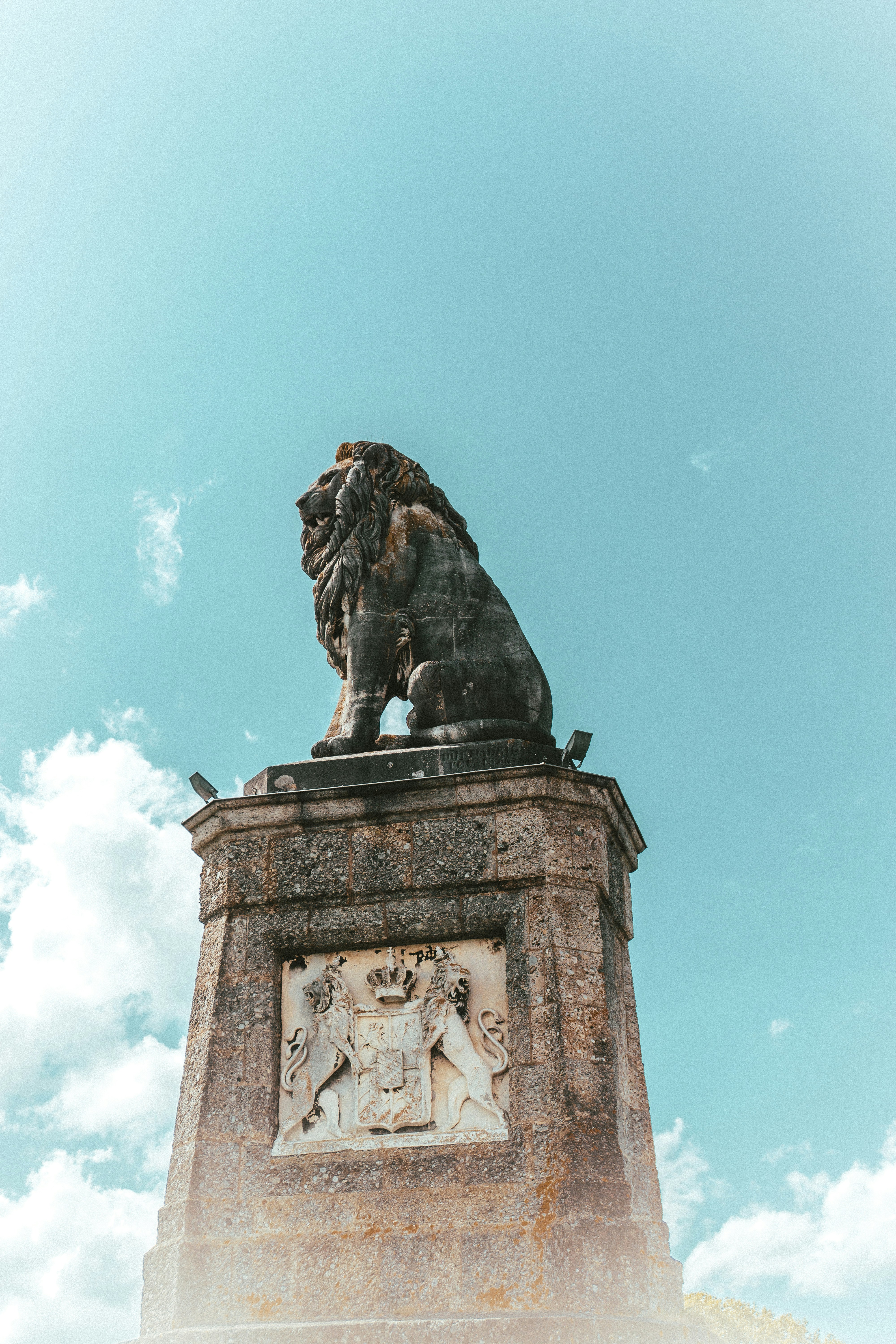 Cerulean Sky and the Granite Guardian: A Lion Statue on a Weathered Pedestal