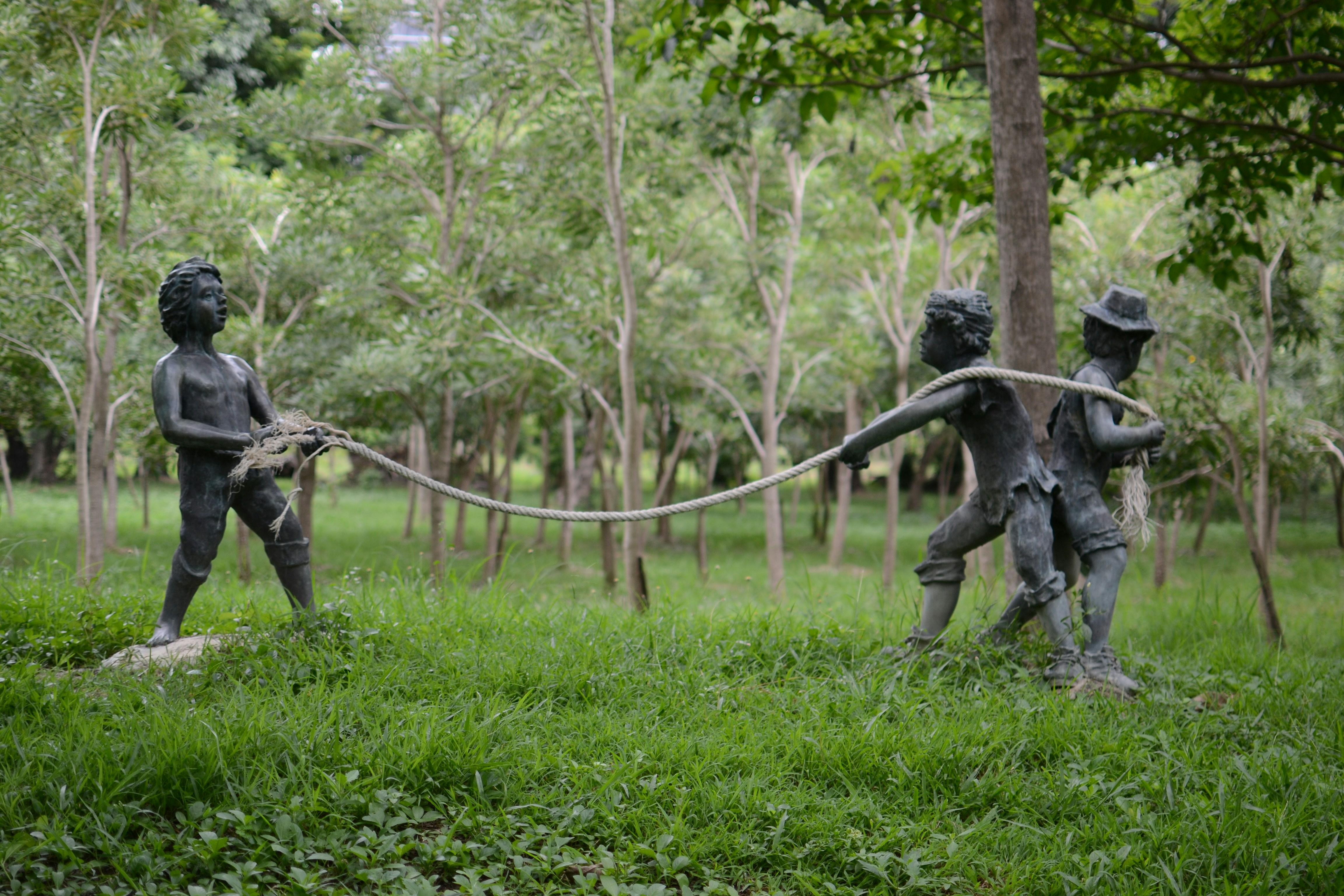 A statue of two children pulling a rope through a forest photo – Free ...