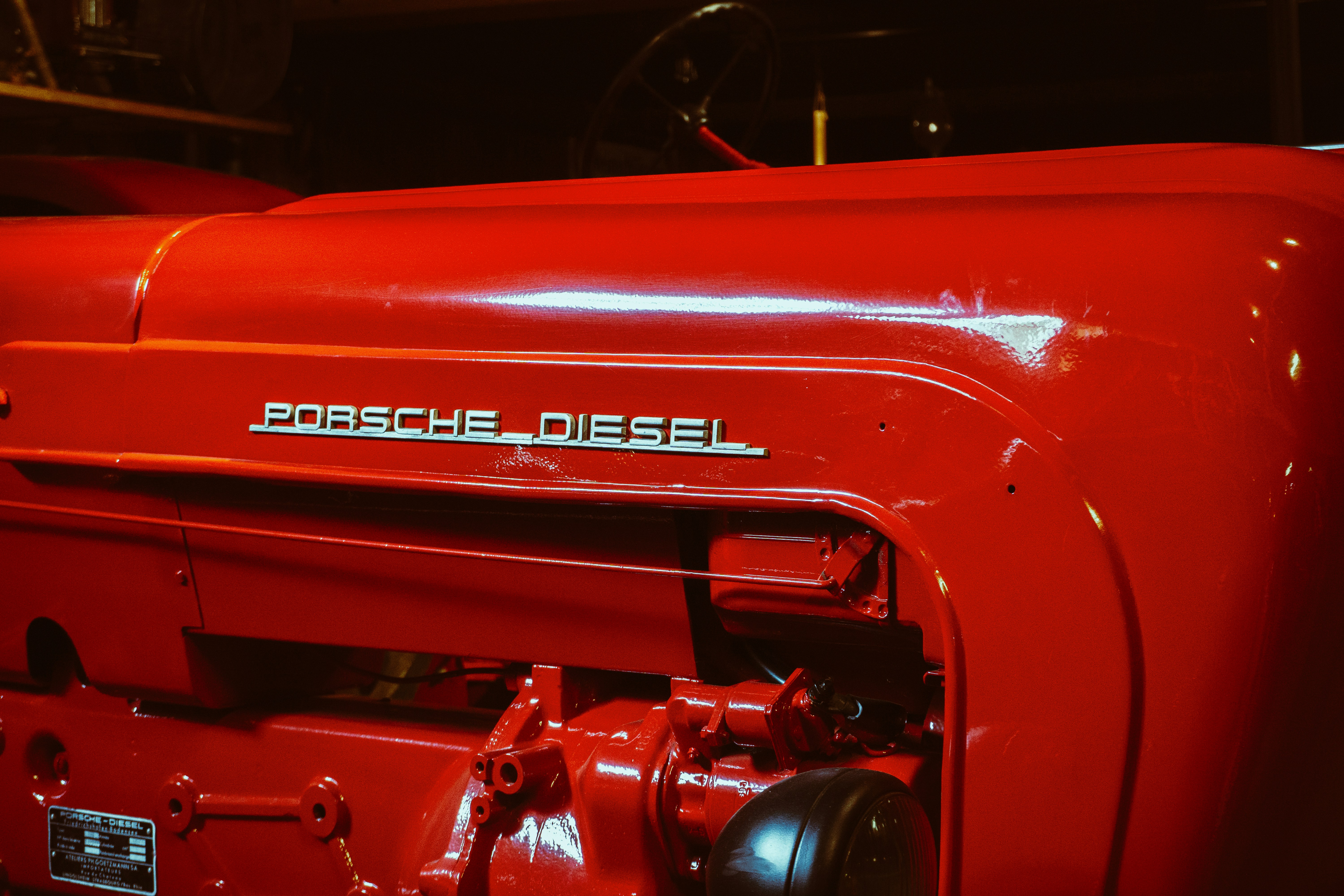 Glossy red Porsche Diesel engine side with logo emblem visible, photographed under warm indoor lighting.