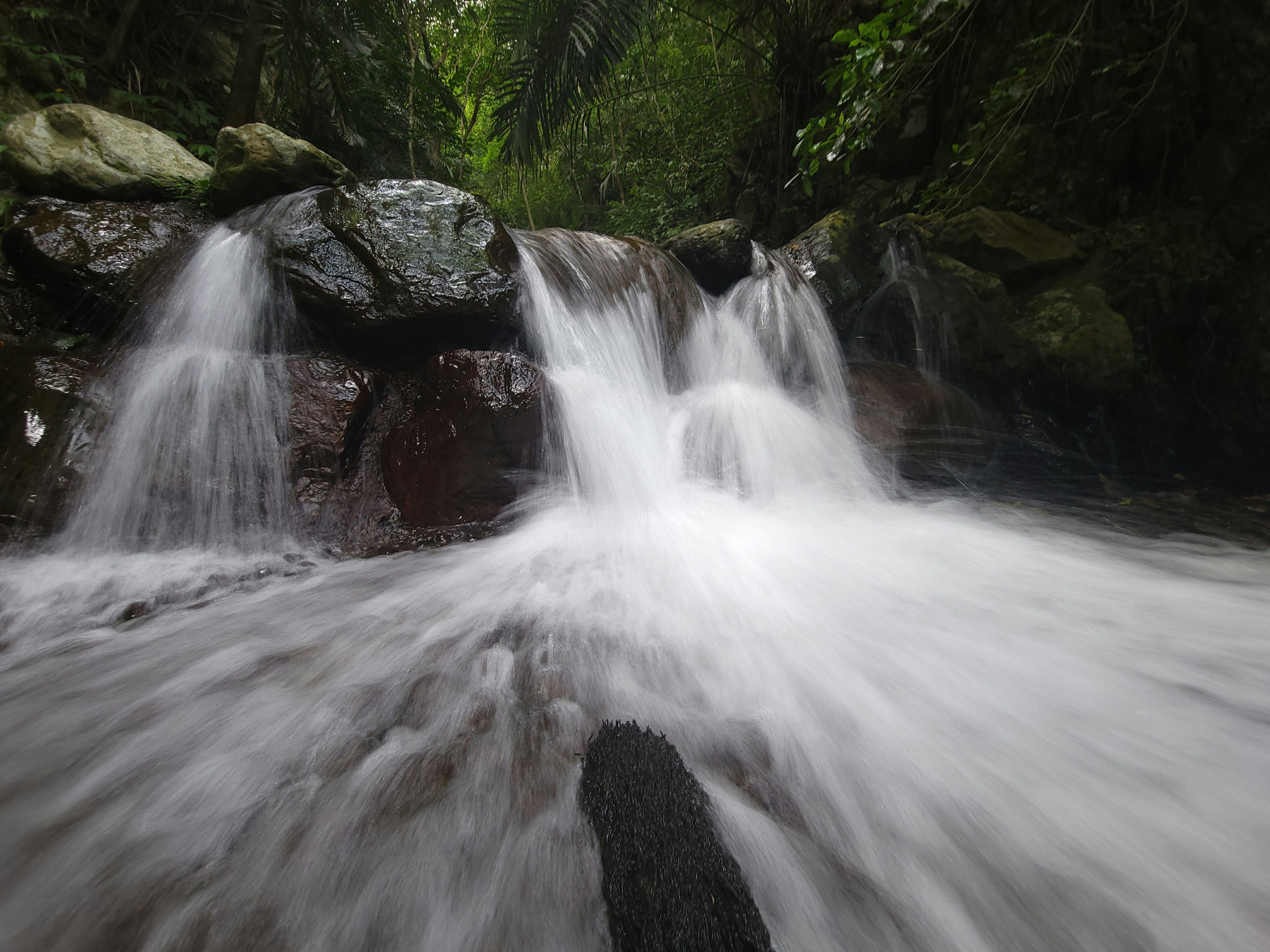 Silky waterfall cascading over moss-covered rocks in a lush forest setting.