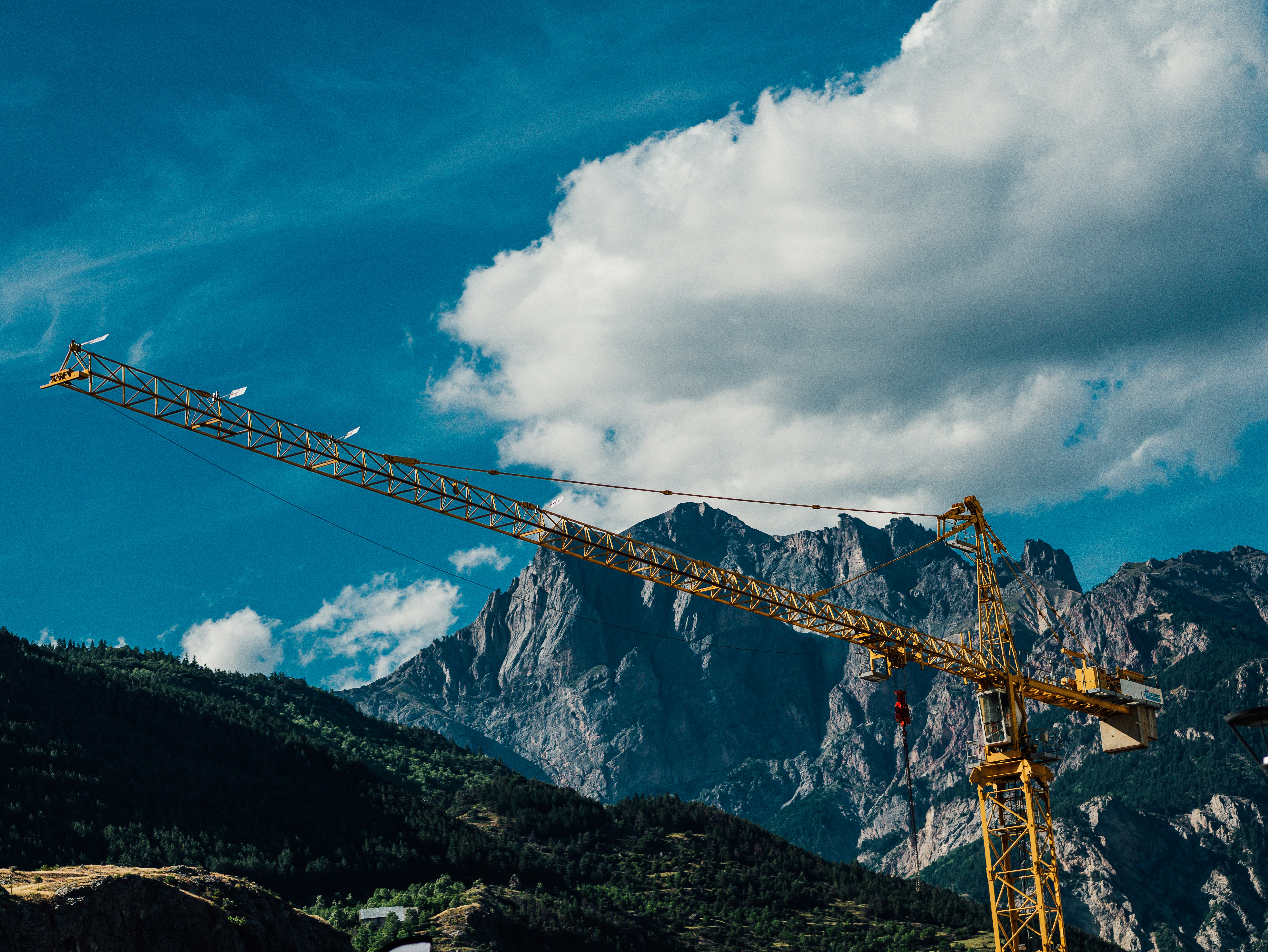 Crane Across the Alpine Rim: A Metal Thread Through Sky and Stone