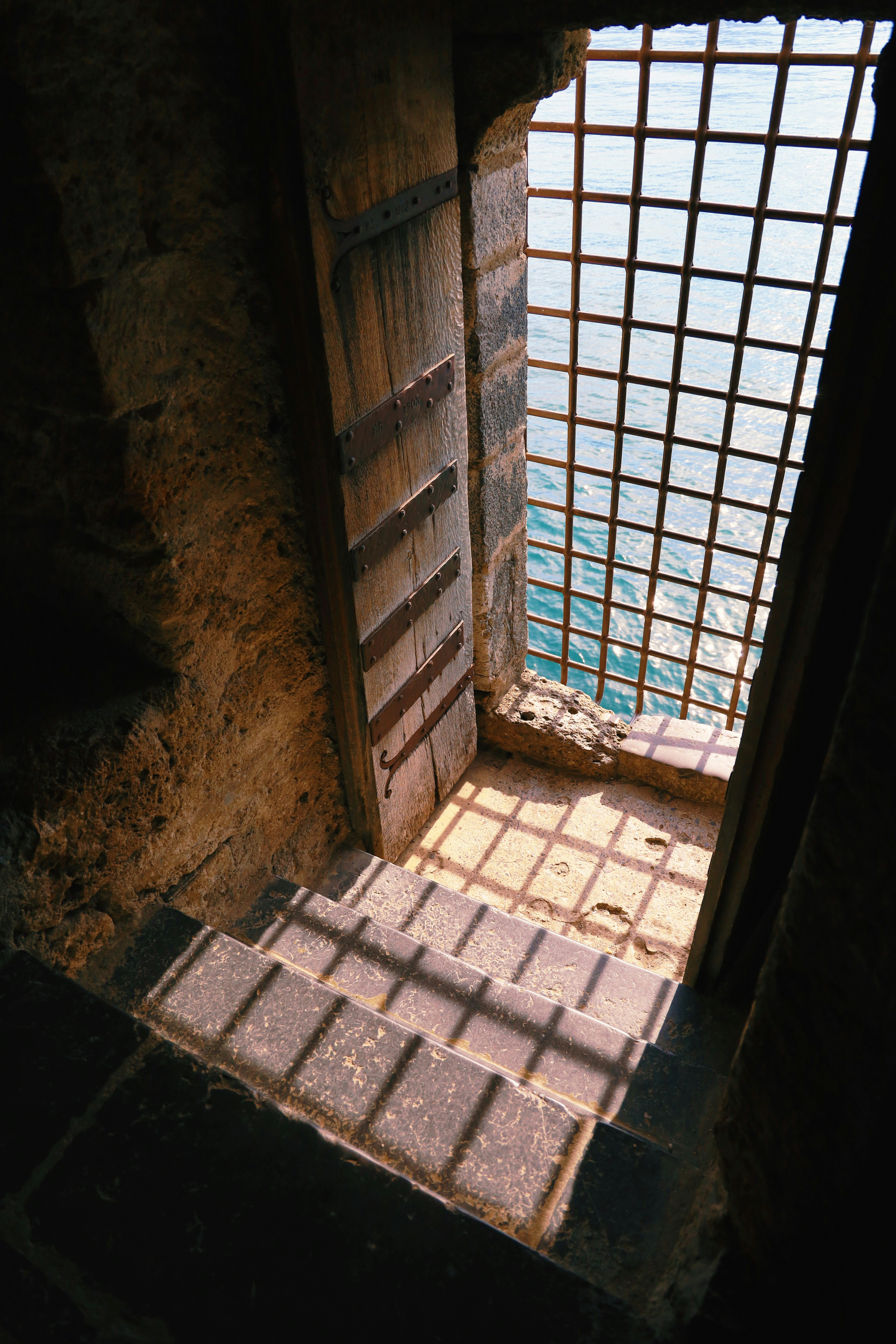 Sunlit Grid Toward the Sea: An Ancient Doorway Cast in Patterned Light