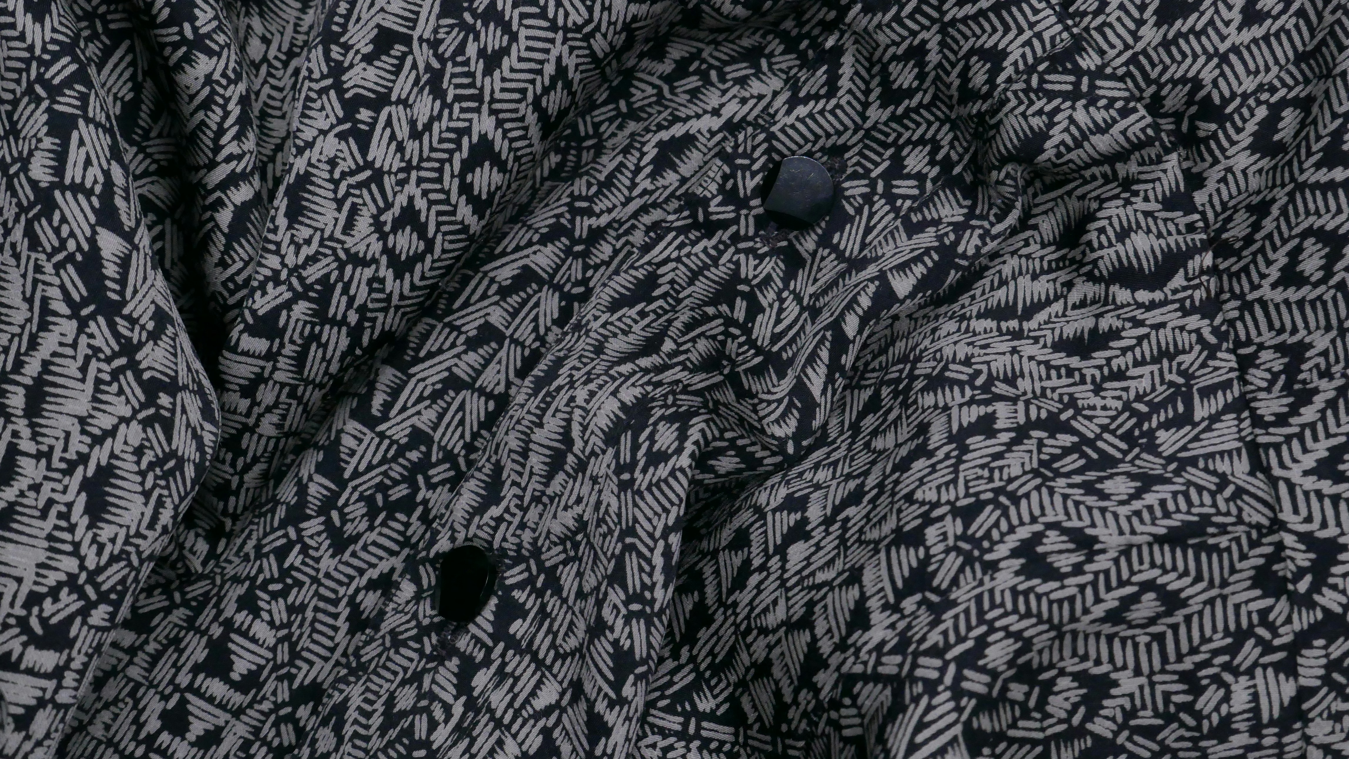Midnight Weave: Close-up of grayscale textured fabric with matte buttons