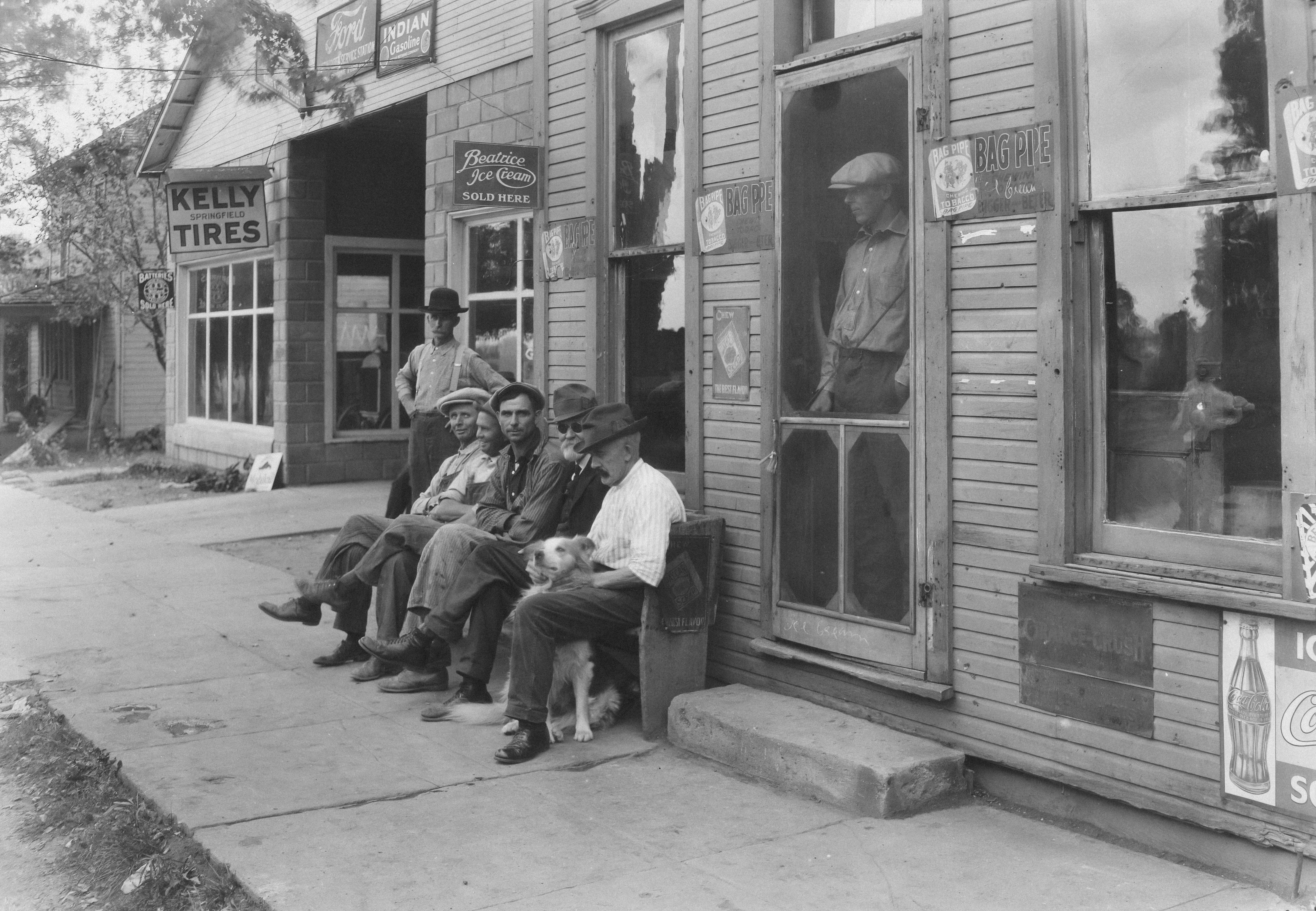 A group of men sitting outside of a store photo – Free Analogue ...