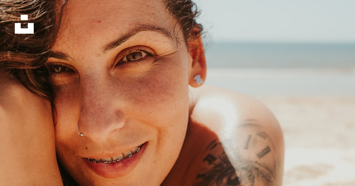 A Woman Laying On The Beach With A Tattoo On Her Arm Photo Free