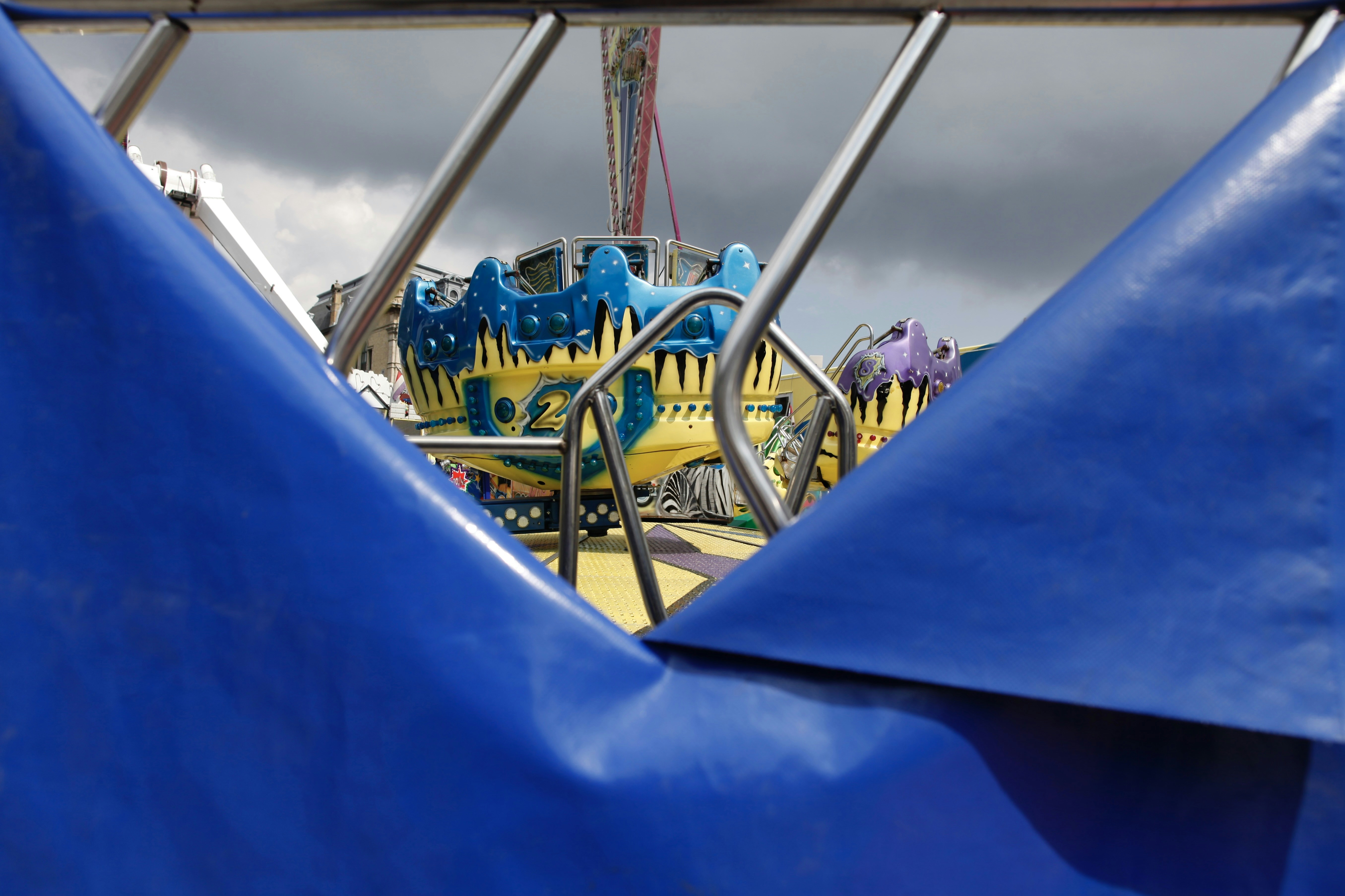 A view of a carnival ride through a blue tarp photo – Free Gent Image ...