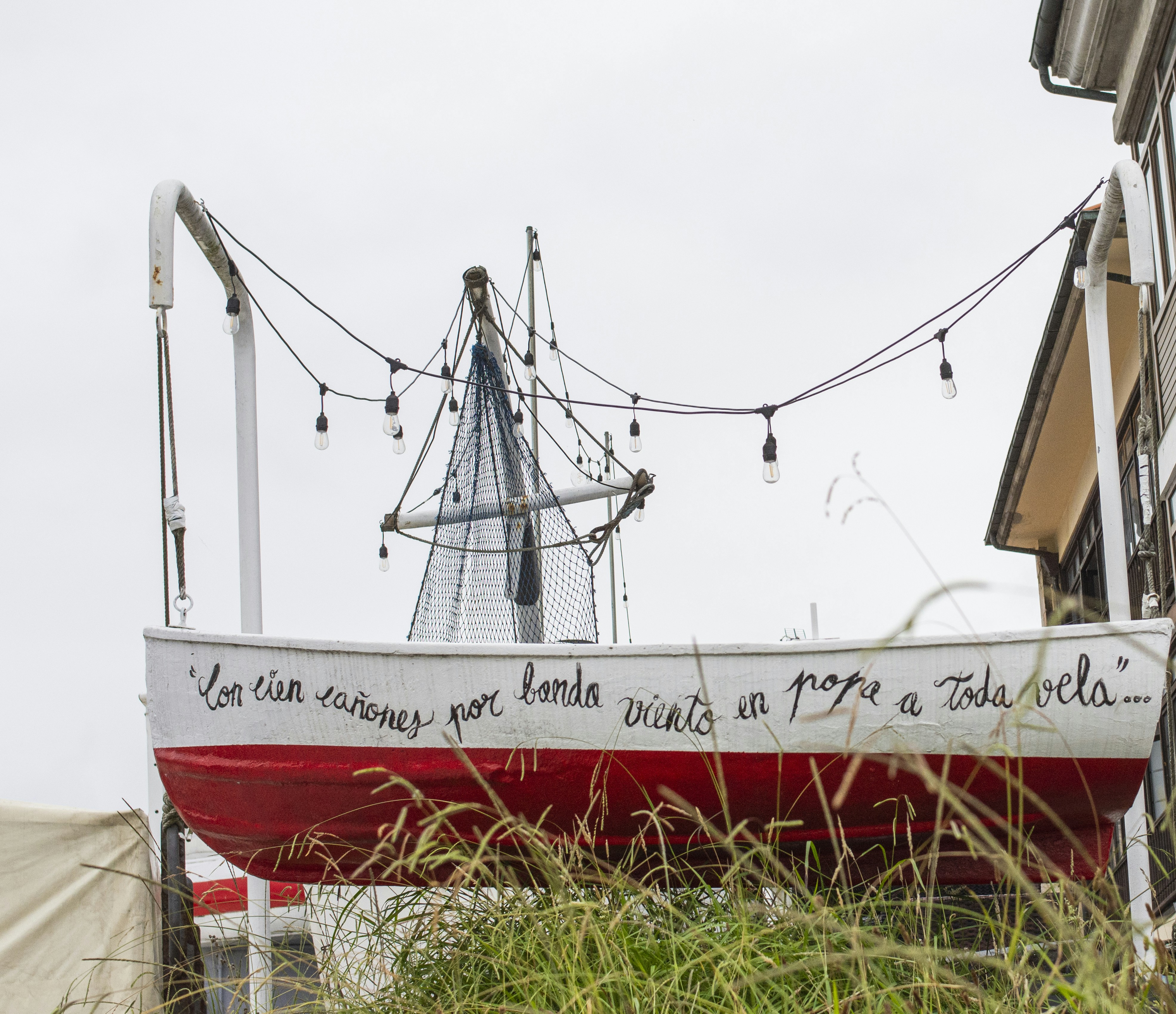A Sailboat Bannered by Strings of Light in a Quiet Street Scene