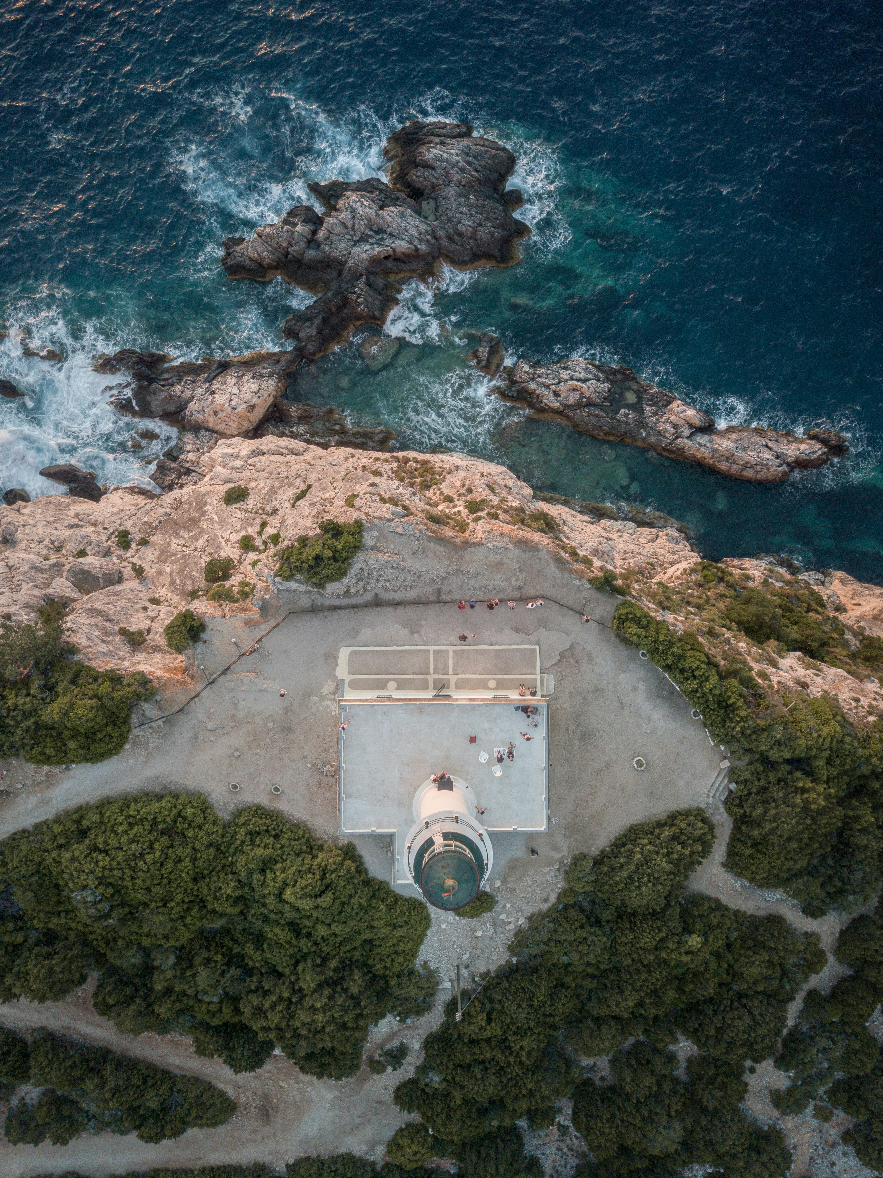 Aerial Beacon Over Turquoise Seas: Cliffside Lighthouse on a Concrete Promenade