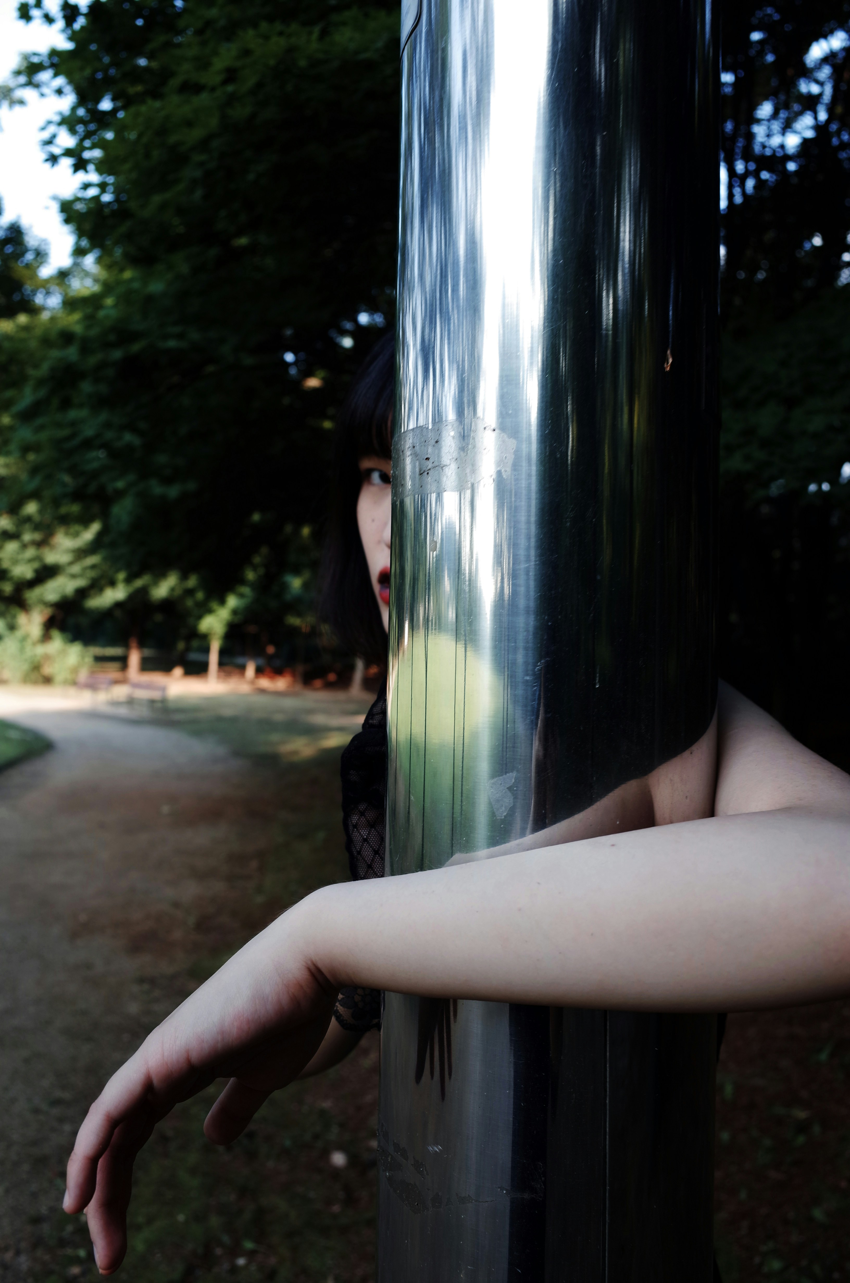 A woman leaning against a pole in a park photo – Free Adult Image on ...