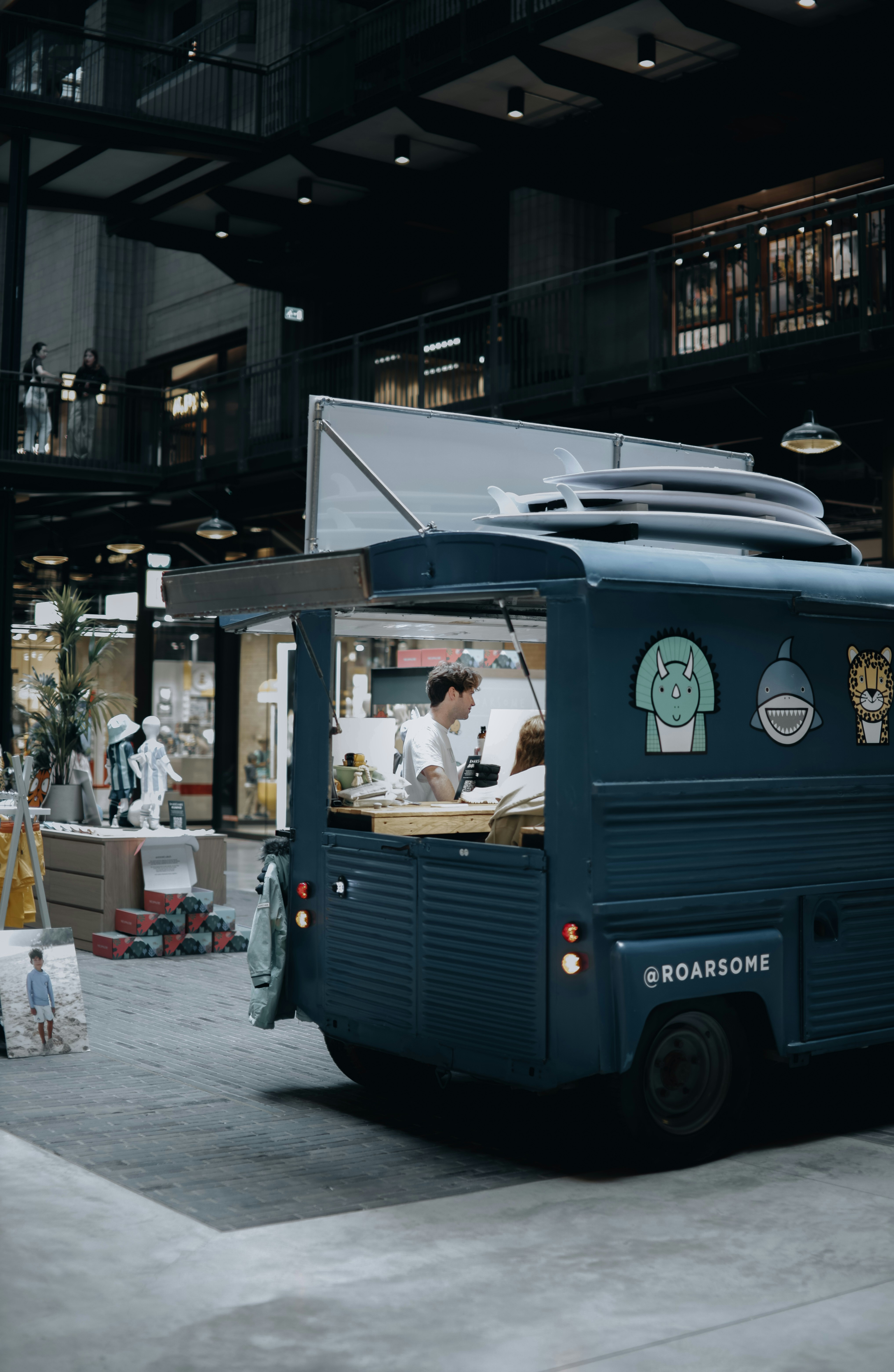 Cartoon-Decaled Blue Food Truck Anchors an Indoor Market Scene