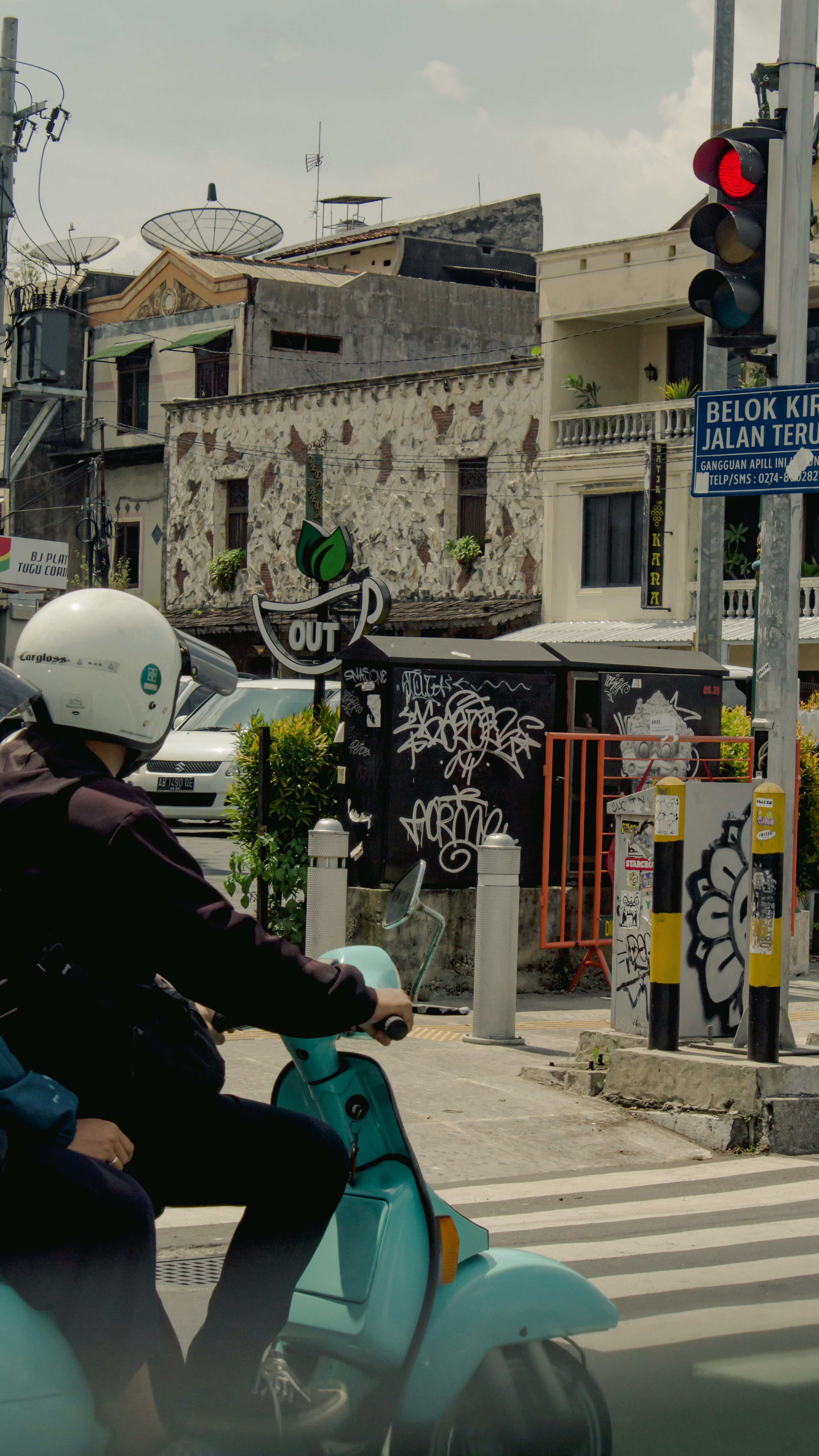 Teal Vespa at a Graffiti-Splashed City Crosswalk