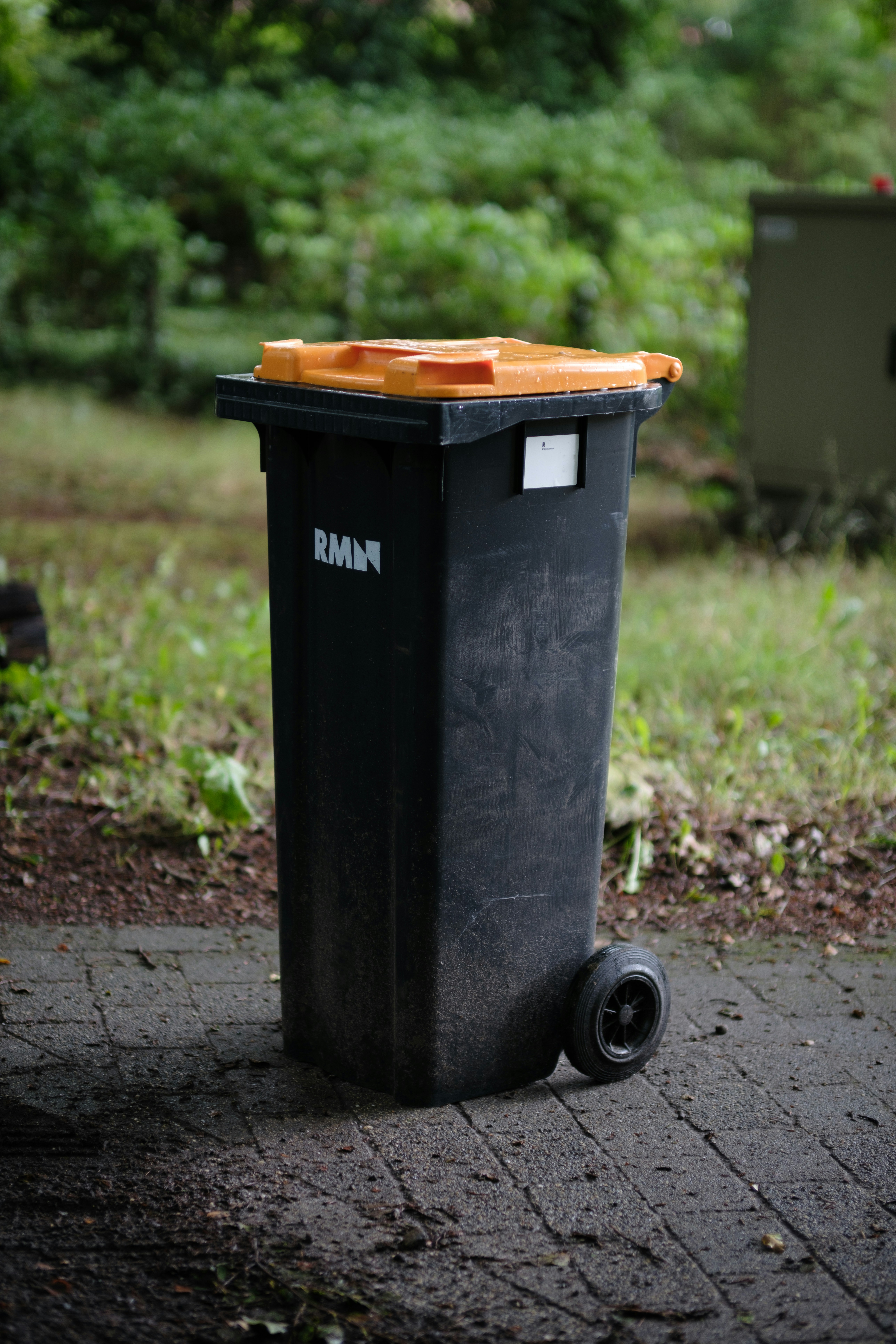 A black trash can sitting on top of a sidewalk photo – Free Mailbox ...