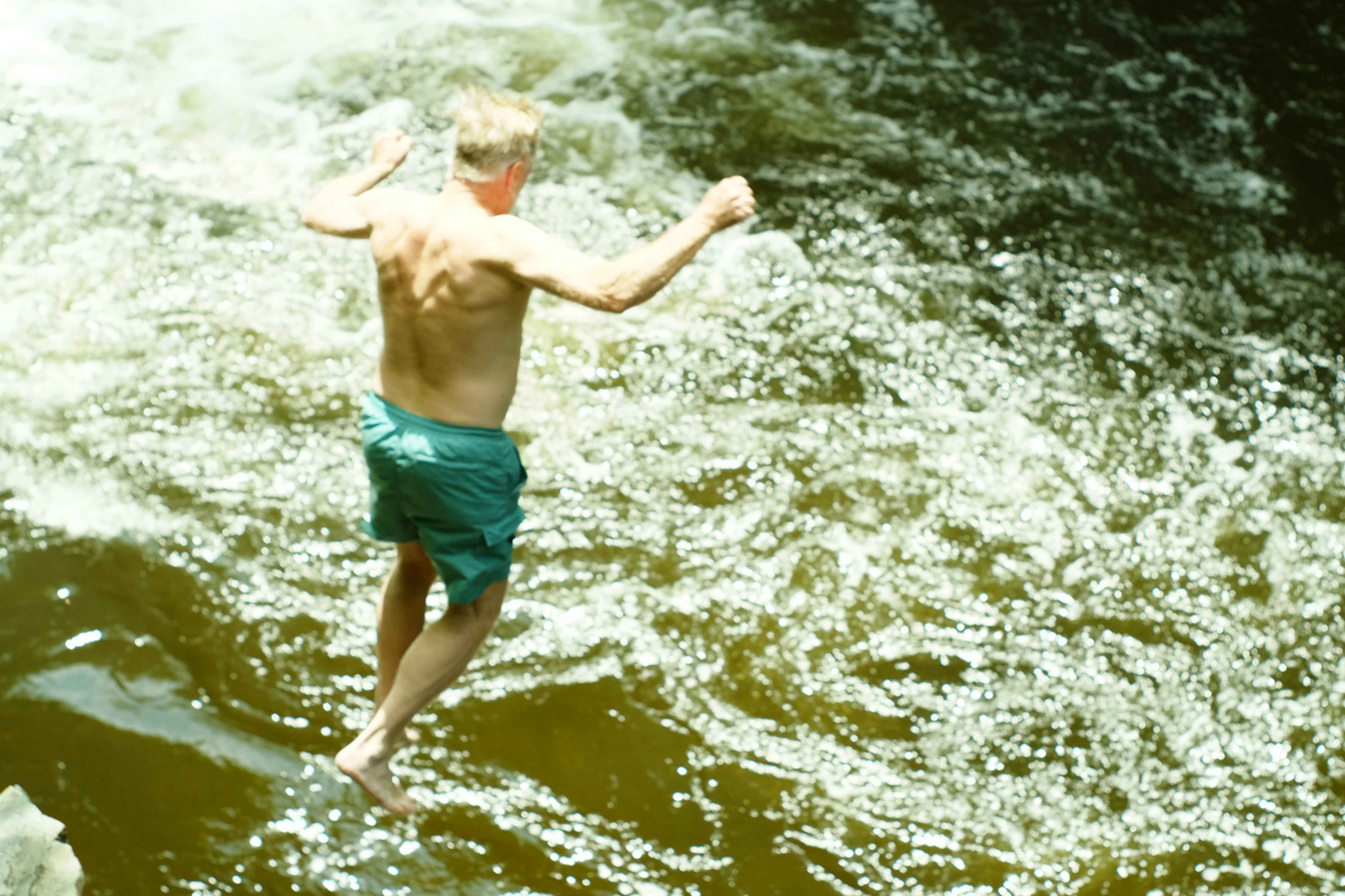 A man jumping off a rock into a river photo – Free Portrait Image on ...