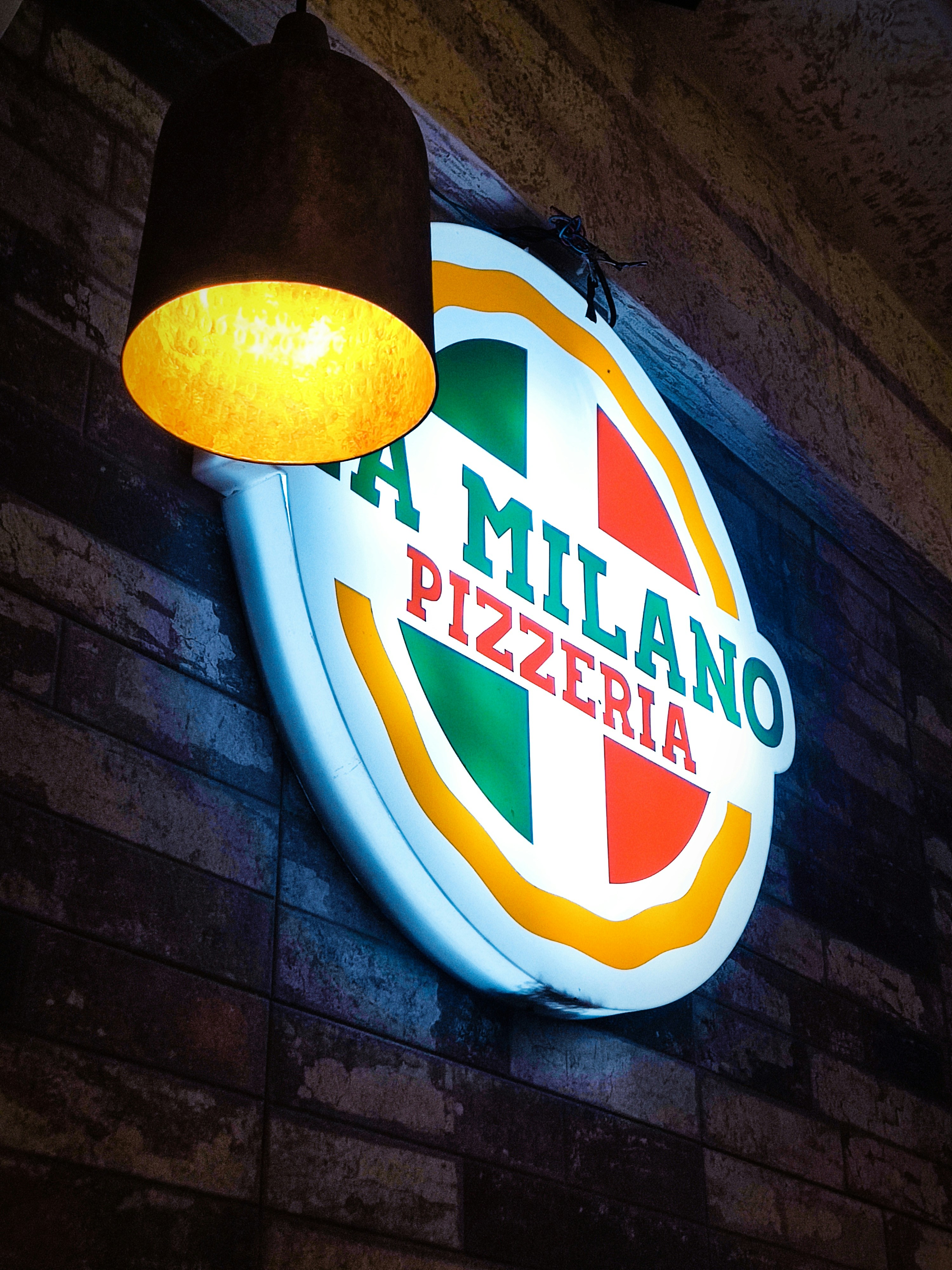 Neon Crest of Milano Pizzeria Under a Warm Night Lamp