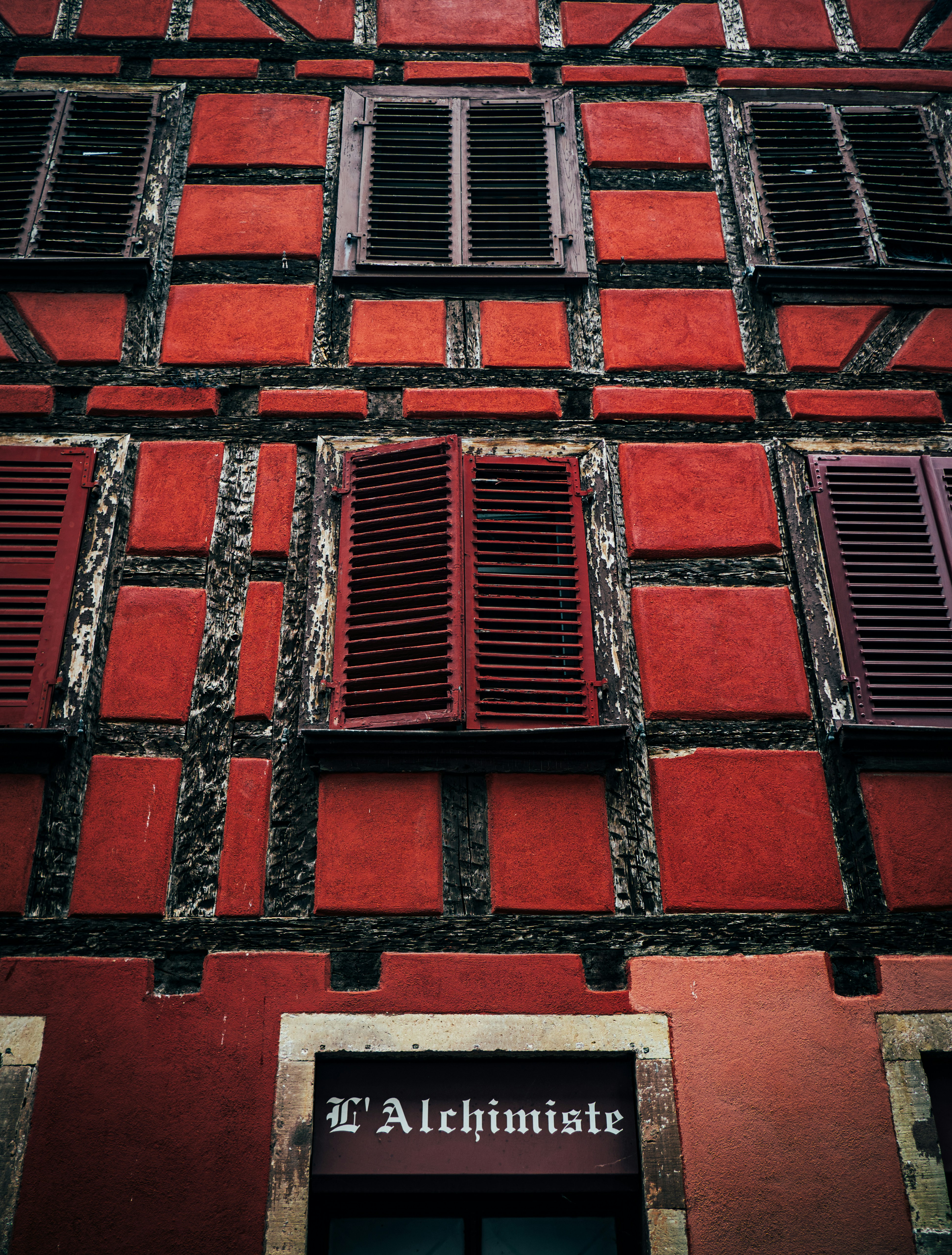 Red Facade with Shuttered Windows and Theatrical Sign