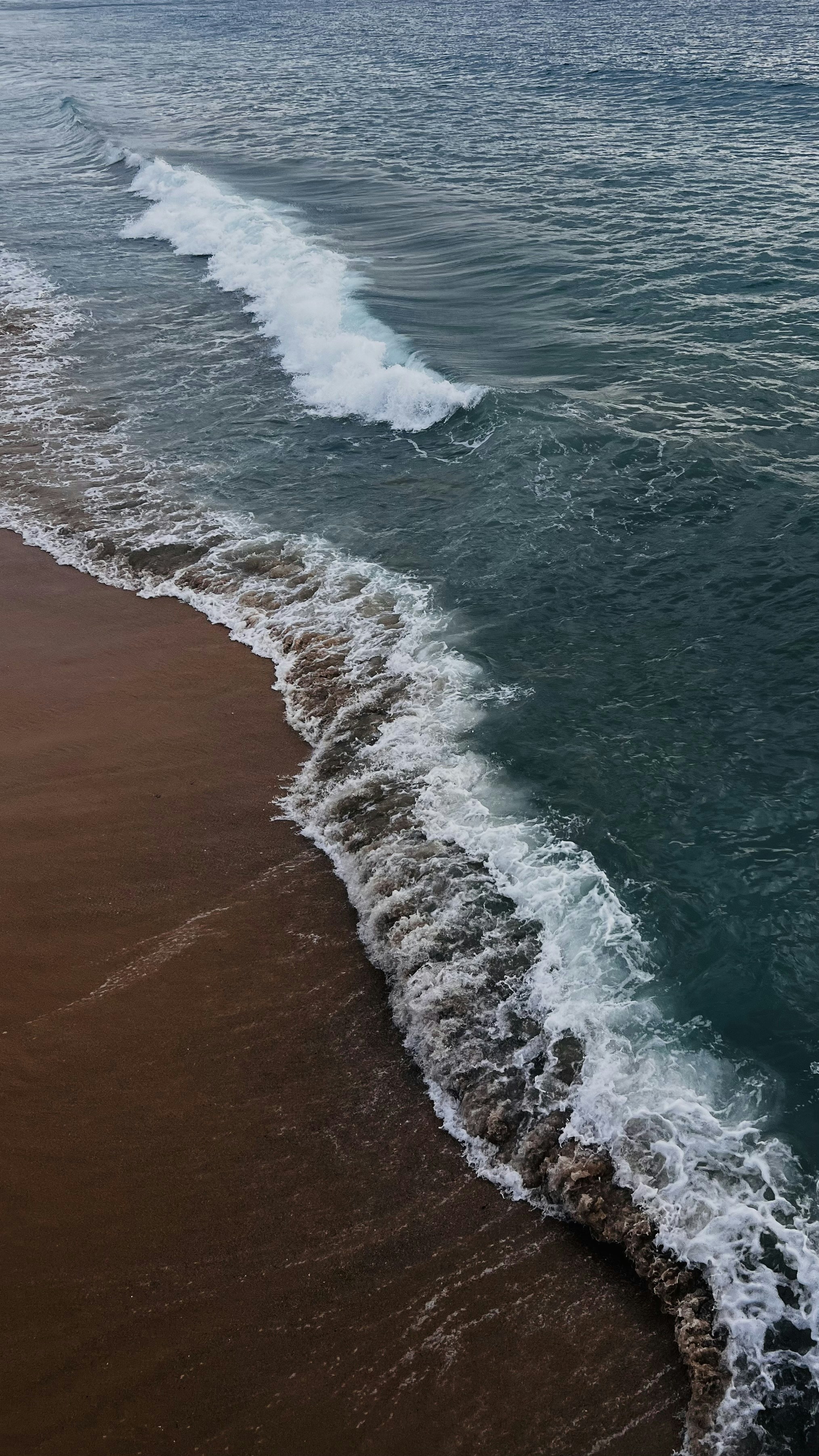 Foto zum Thema Ein Strand mit Wellen, die ins und aus dem Wasser kommen ...