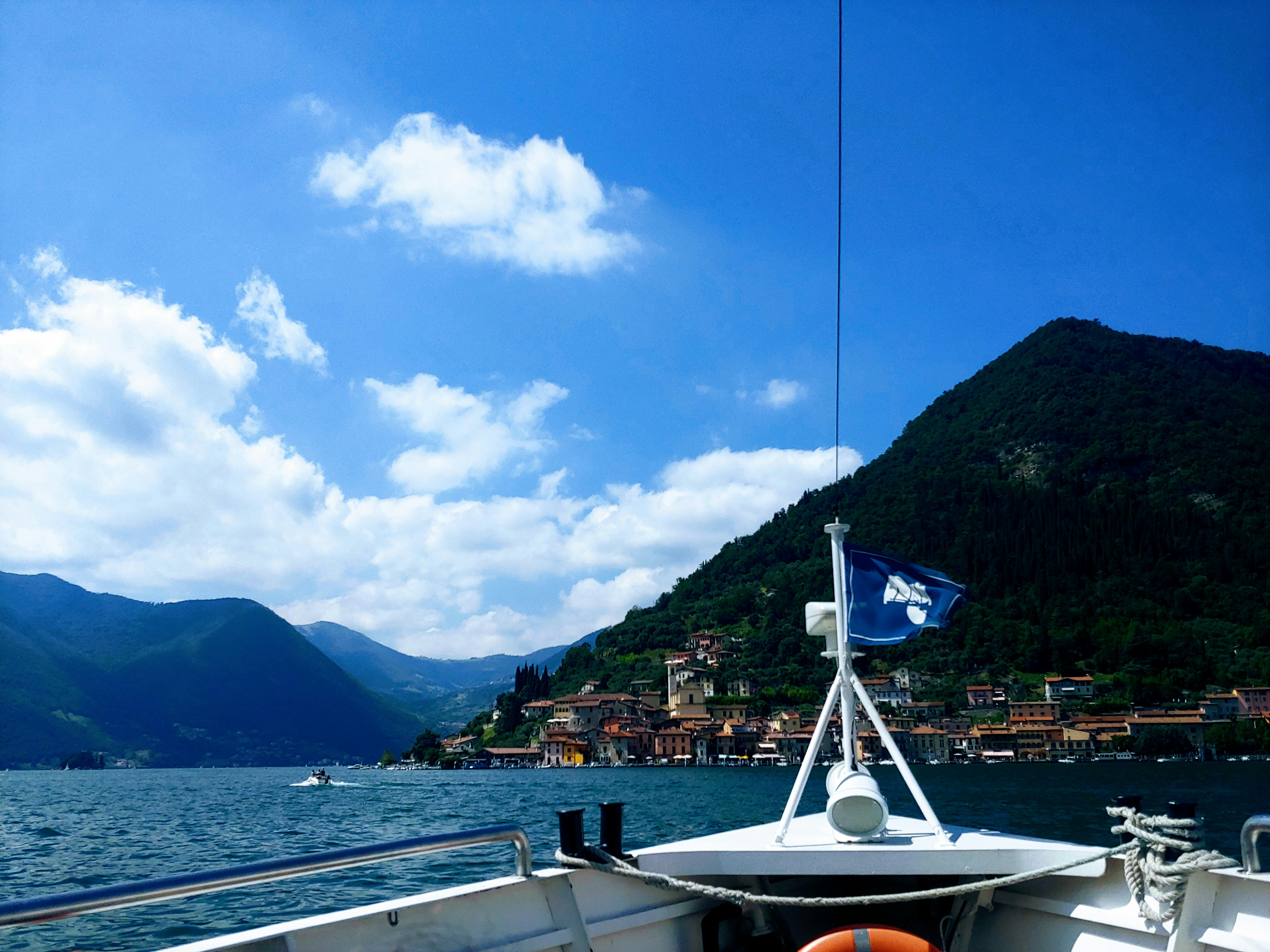 Boat navigating a picturesque lake with mountainous landscape under a bright blue sky.