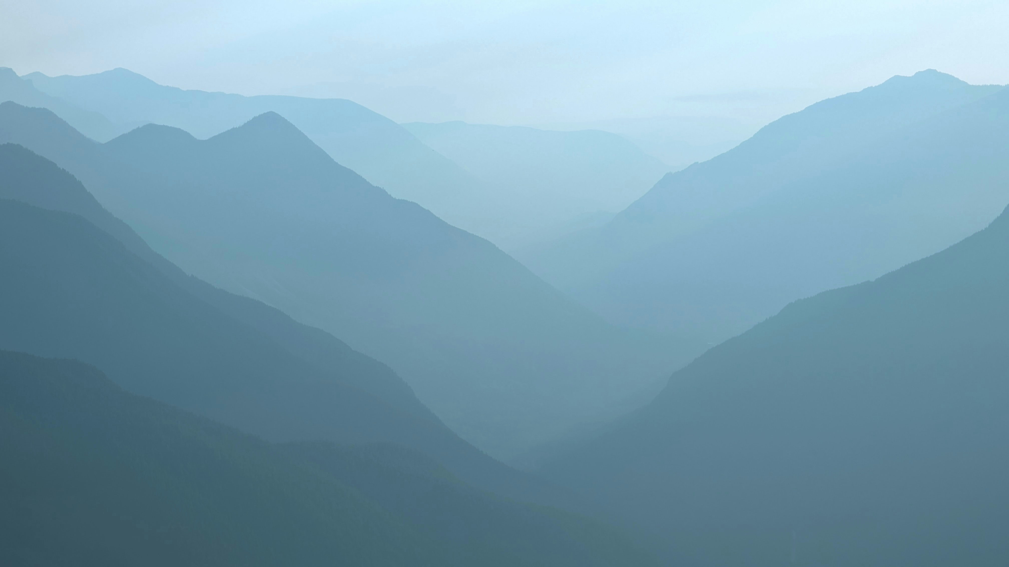 Layered blue mountains fade into pale haze, creating a tranquil horizon with deep atmospheric perspective. A landscape photograph emphasizing distant tones and quiet depth.