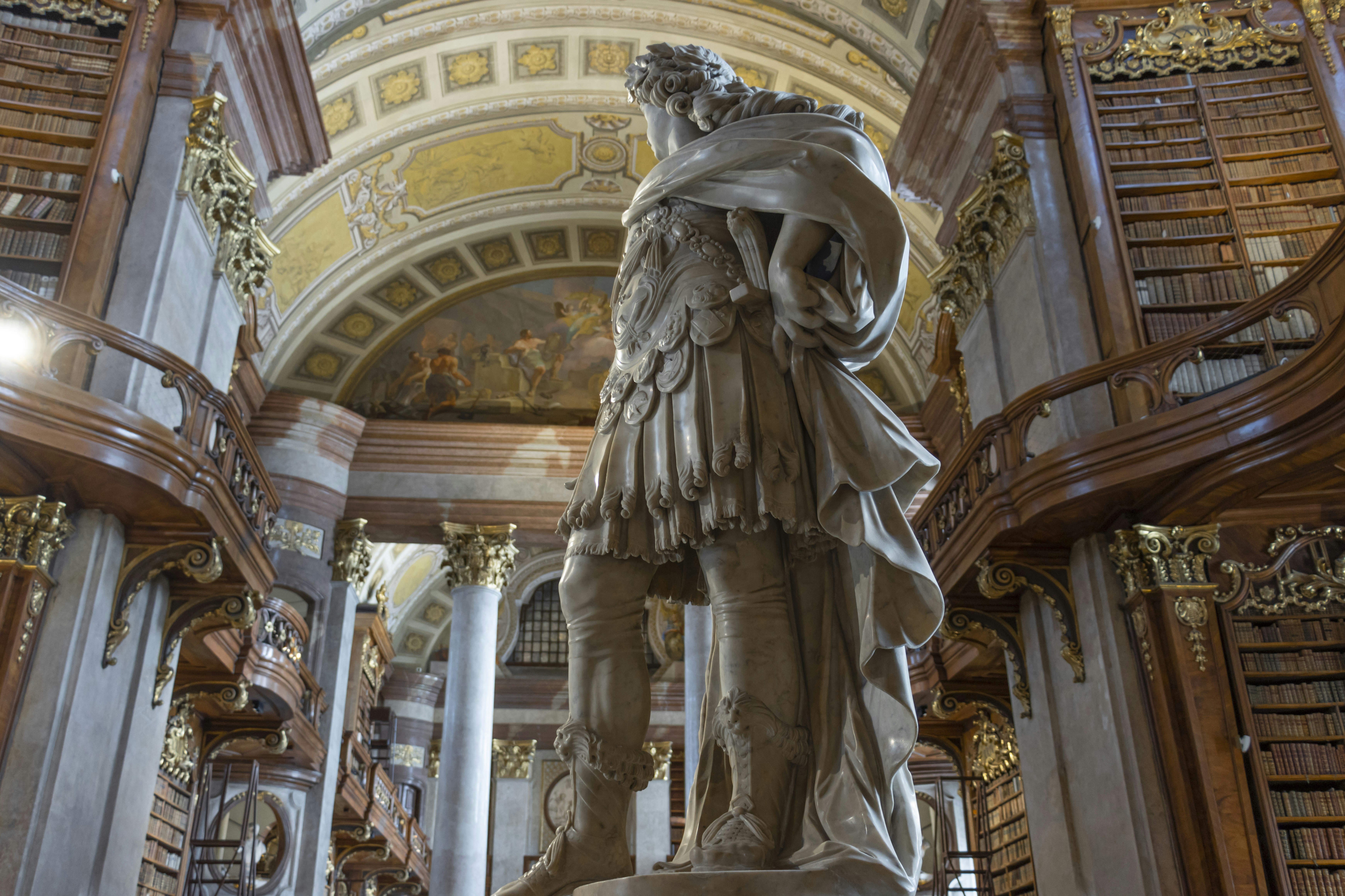 A statue of a man holding a book in a library photo – Free Building ...