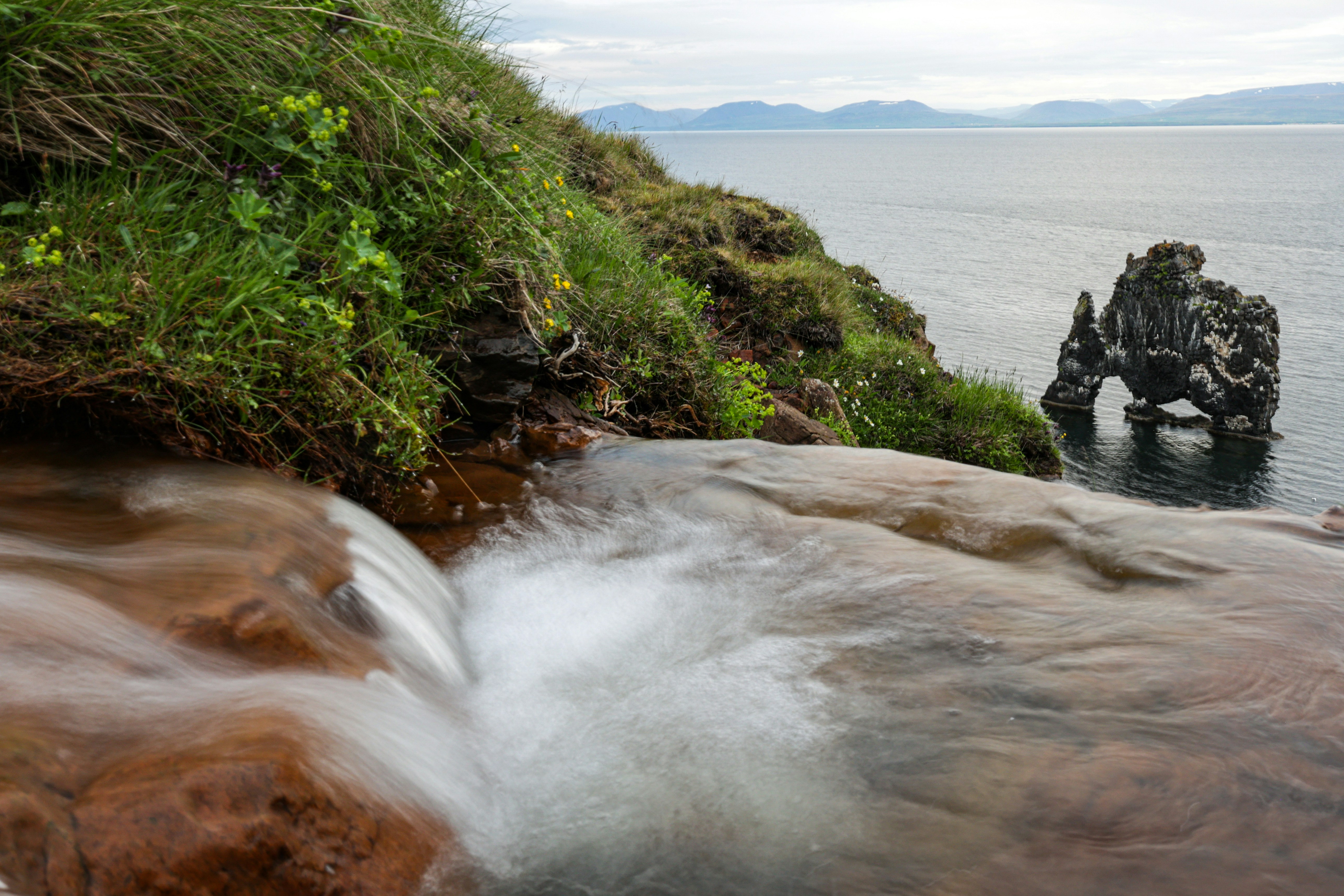 Red Rock Cascade Framing a Sea Arch at the Coastal Edge
