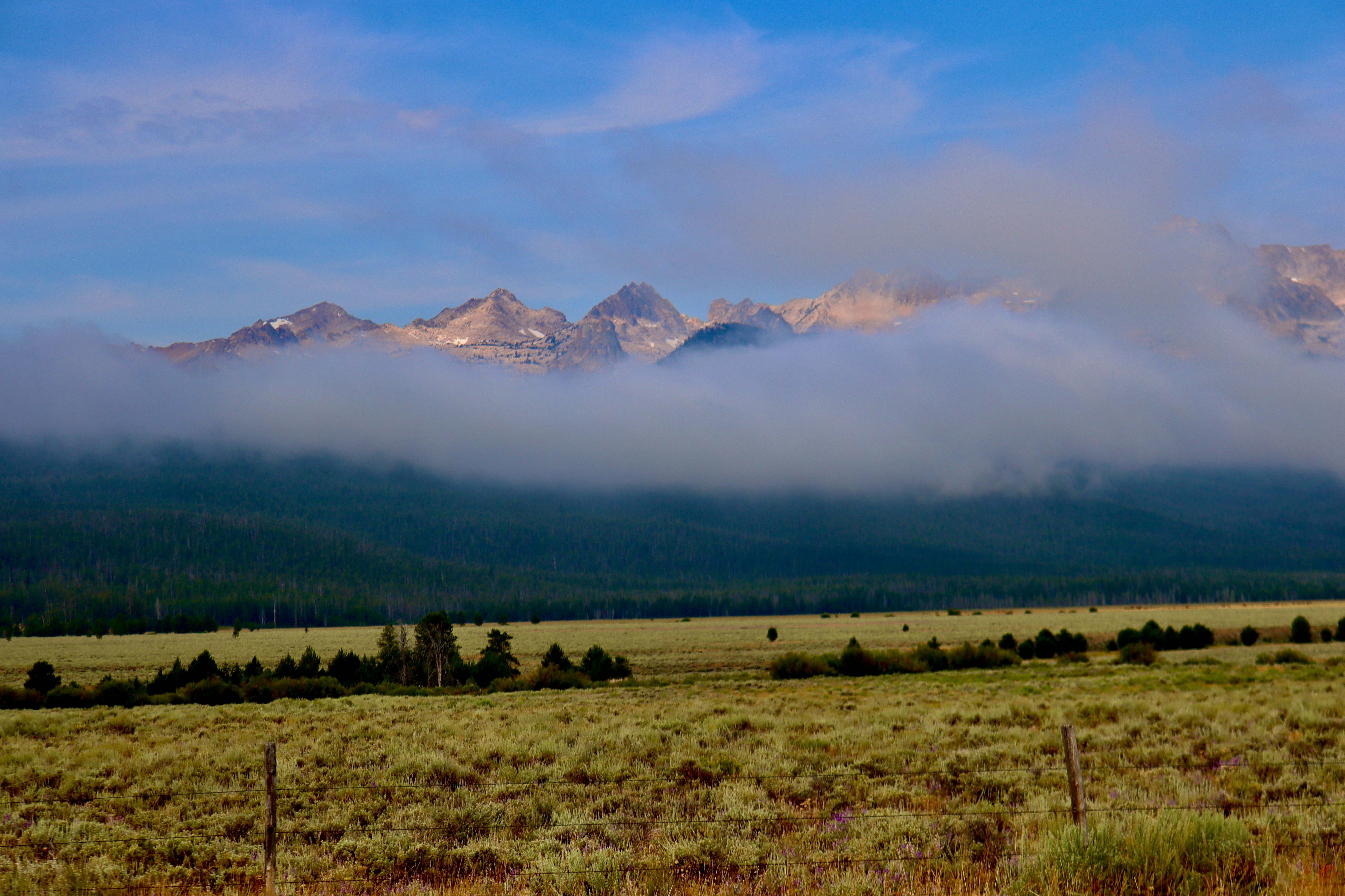 A field with a fence and mountains in the background photo – Free Sawtooth range Image on Unsplash