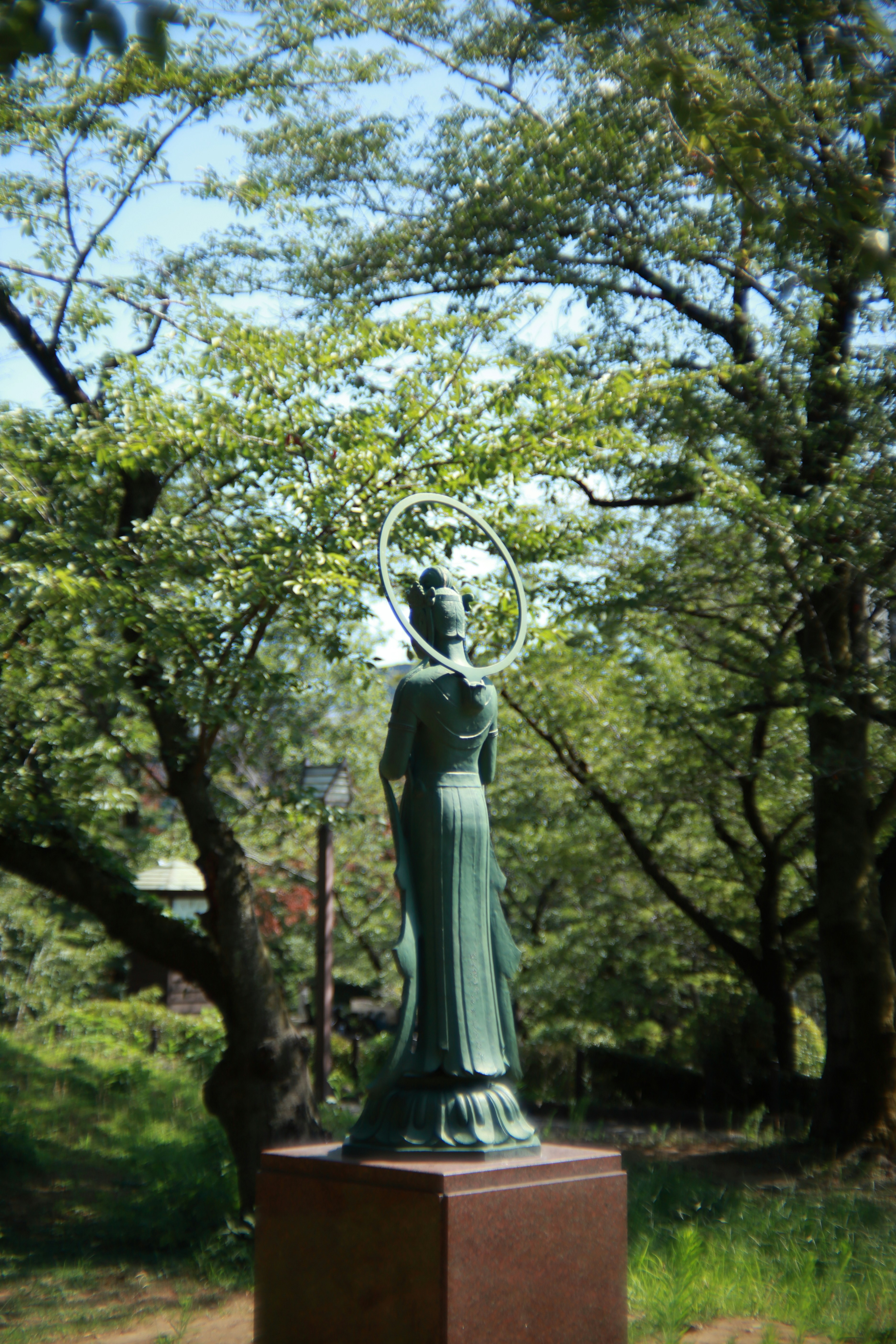 Halo Over the Grove: A Veiled Statue Stands Amid Green Light