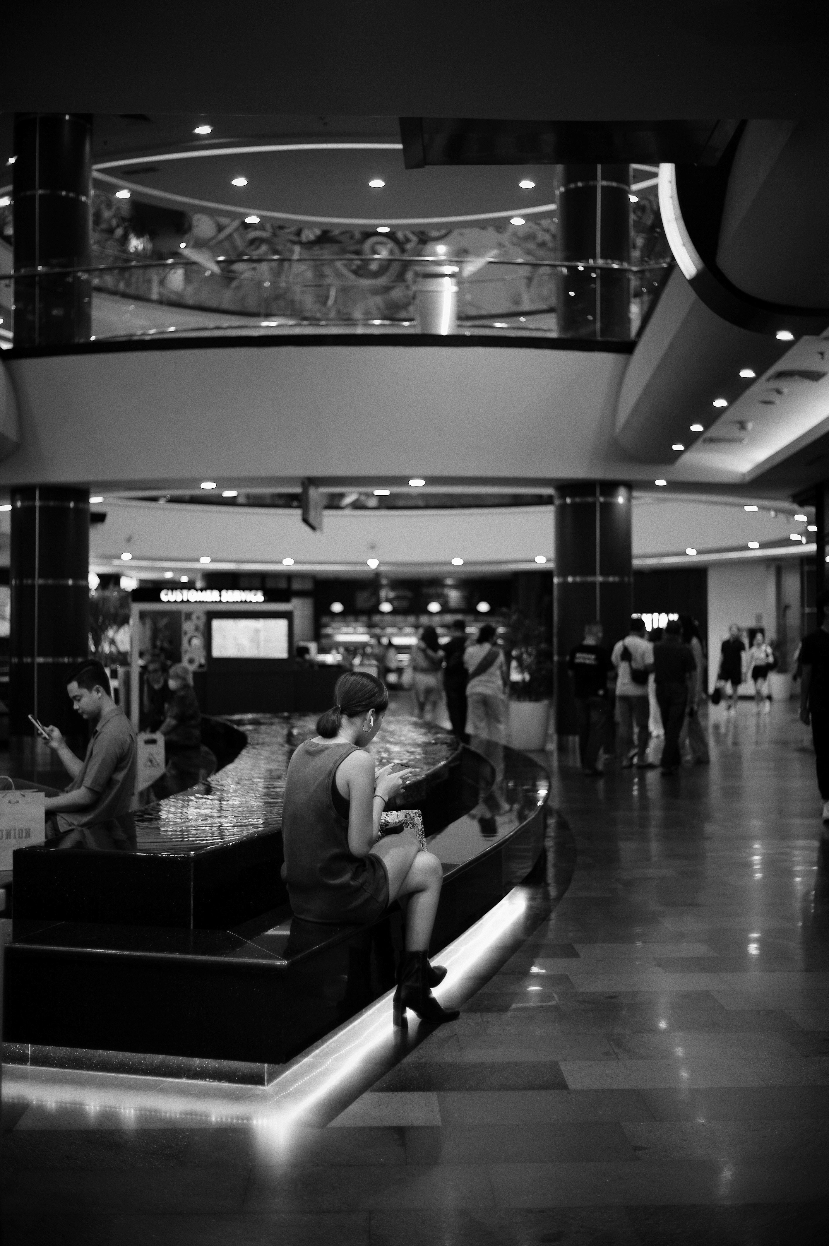 Une femme assise sur un banc dans un centre commercial photo – Photo ...