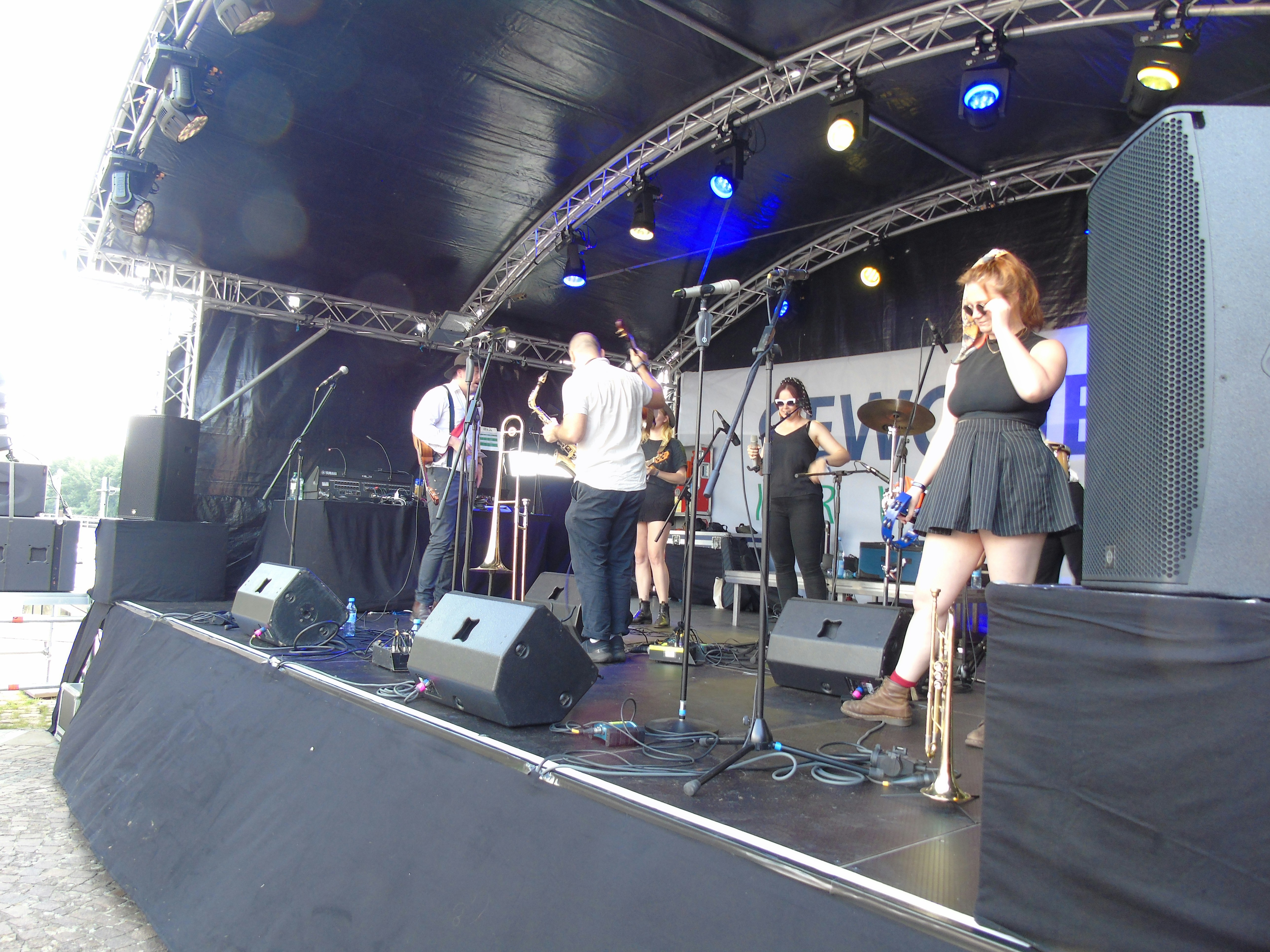 Midstage Groove: Musicians in a Sunlit Outdoor Concert