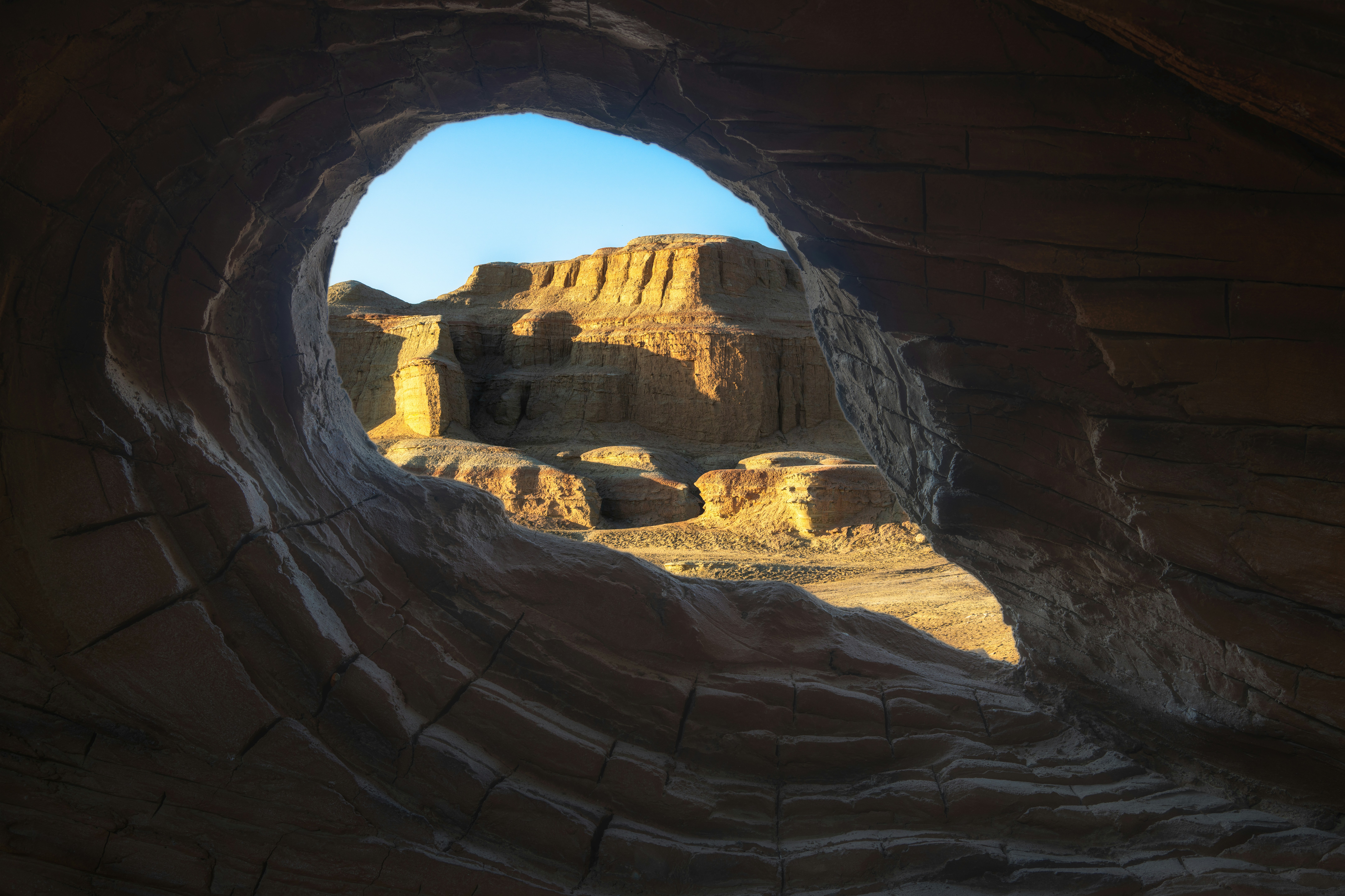 A hole in a rock formation with a mountain in the background photo ...