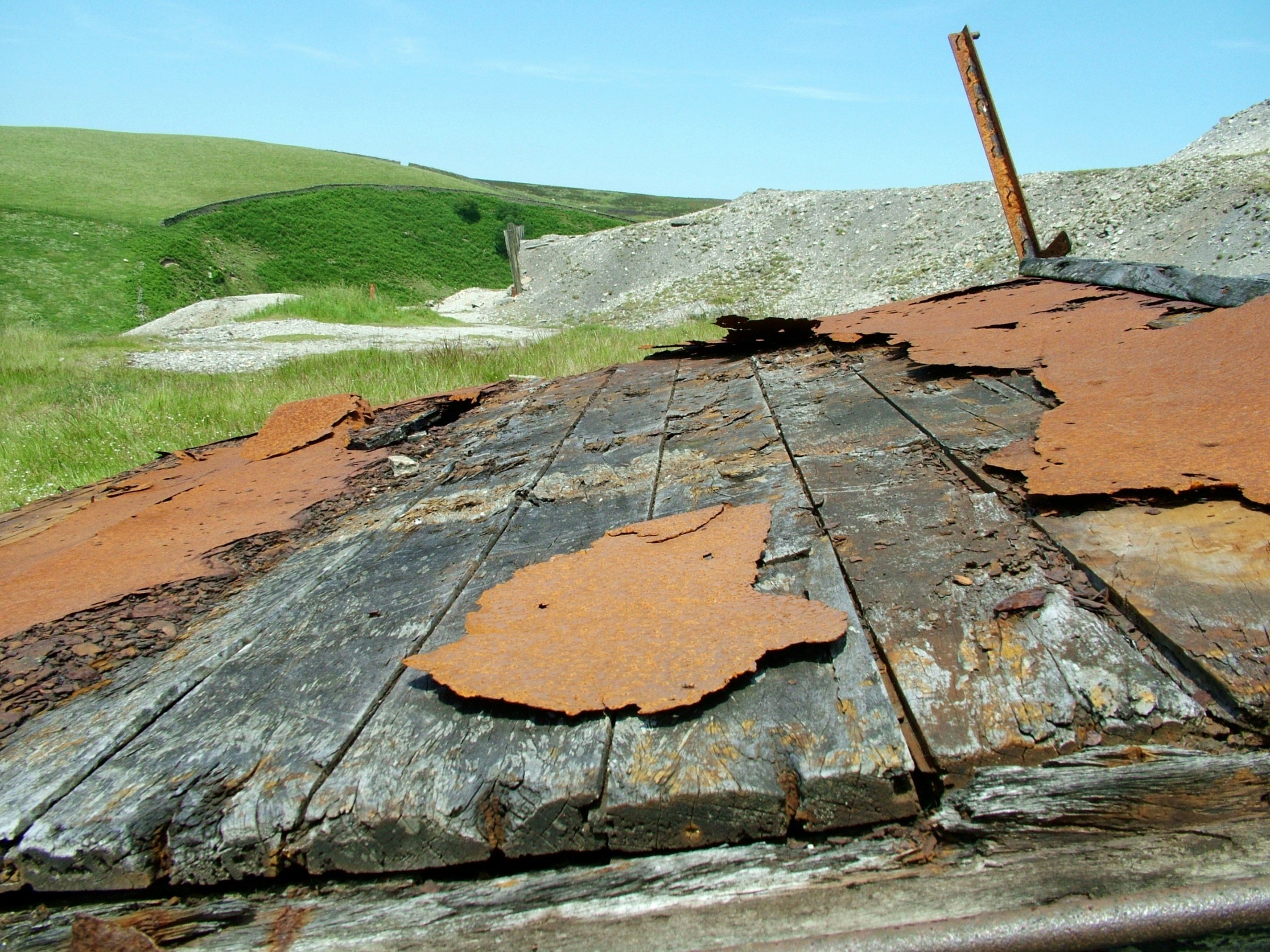 a rusted wooden surface with a green hill in the background
