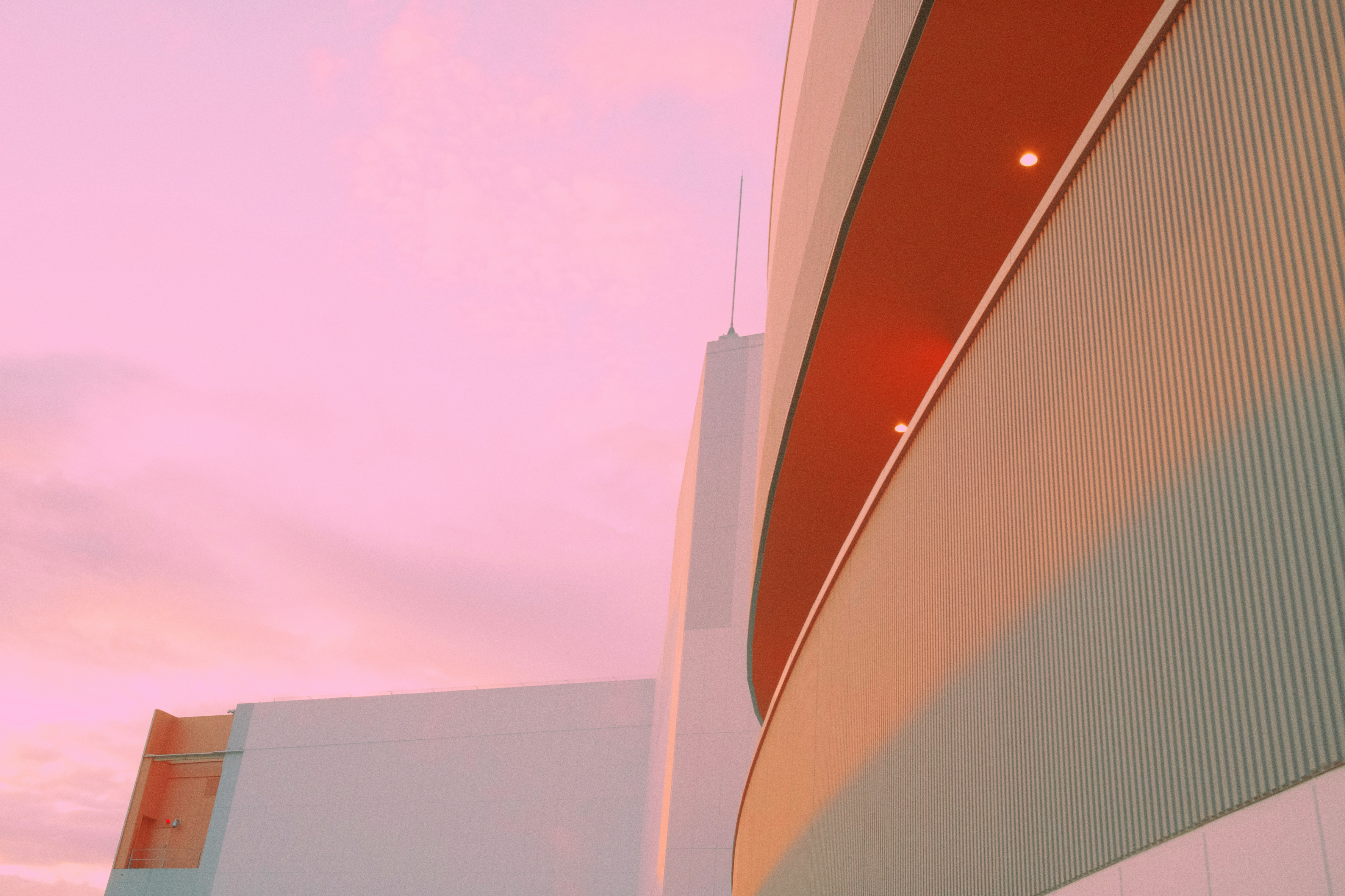 Pastel Facade: The Pink Sky Meets a Curved Modernist Corner