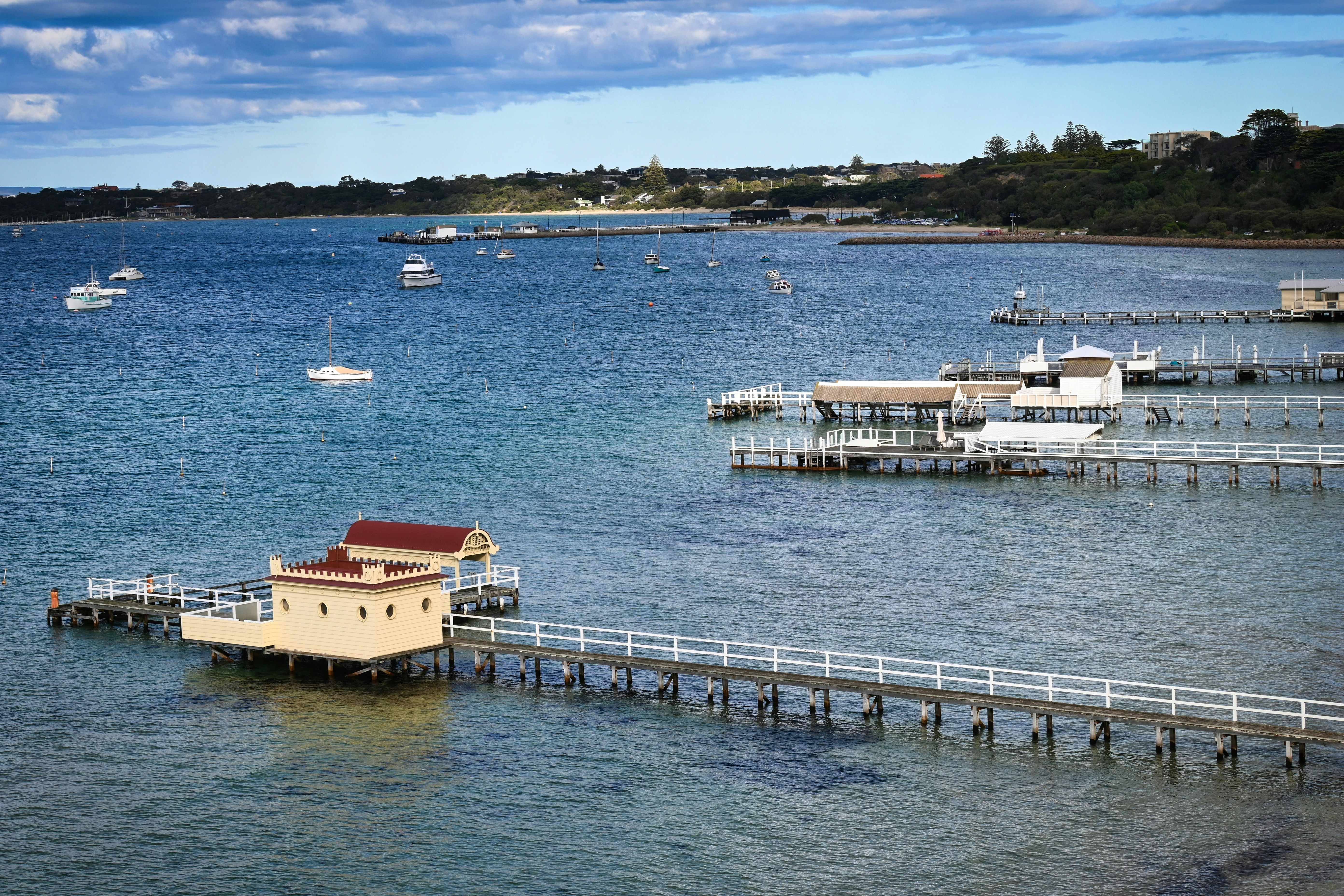 Charming waterfront structures on wooden piers, surrounded by tranquil waters and boats, under a cloudy sky.