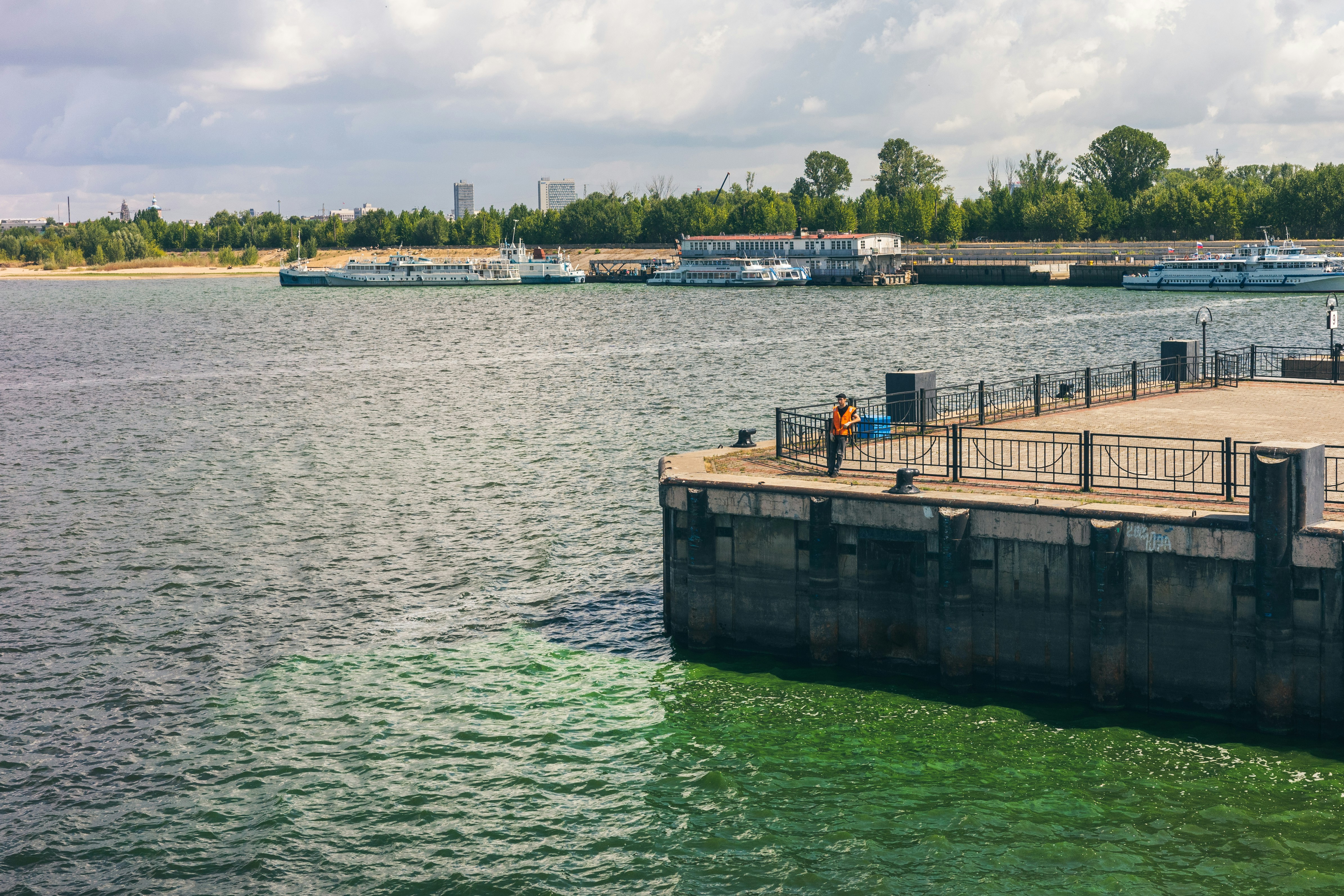 People relaxing on a pier extending into calm waters under a partly cloudy sky.
