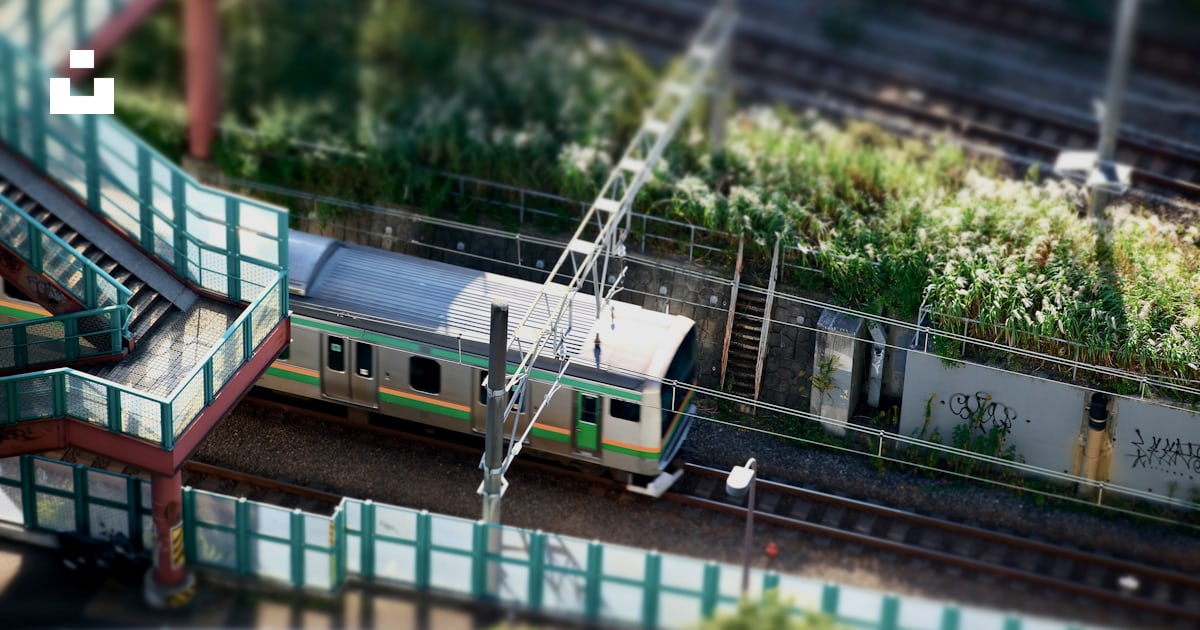 Un treno che viaggia lungo i binari del treno accanto a un tetto verde ... Un treno che viaggia lungo i binari del treno accanto a un tetto verde ...