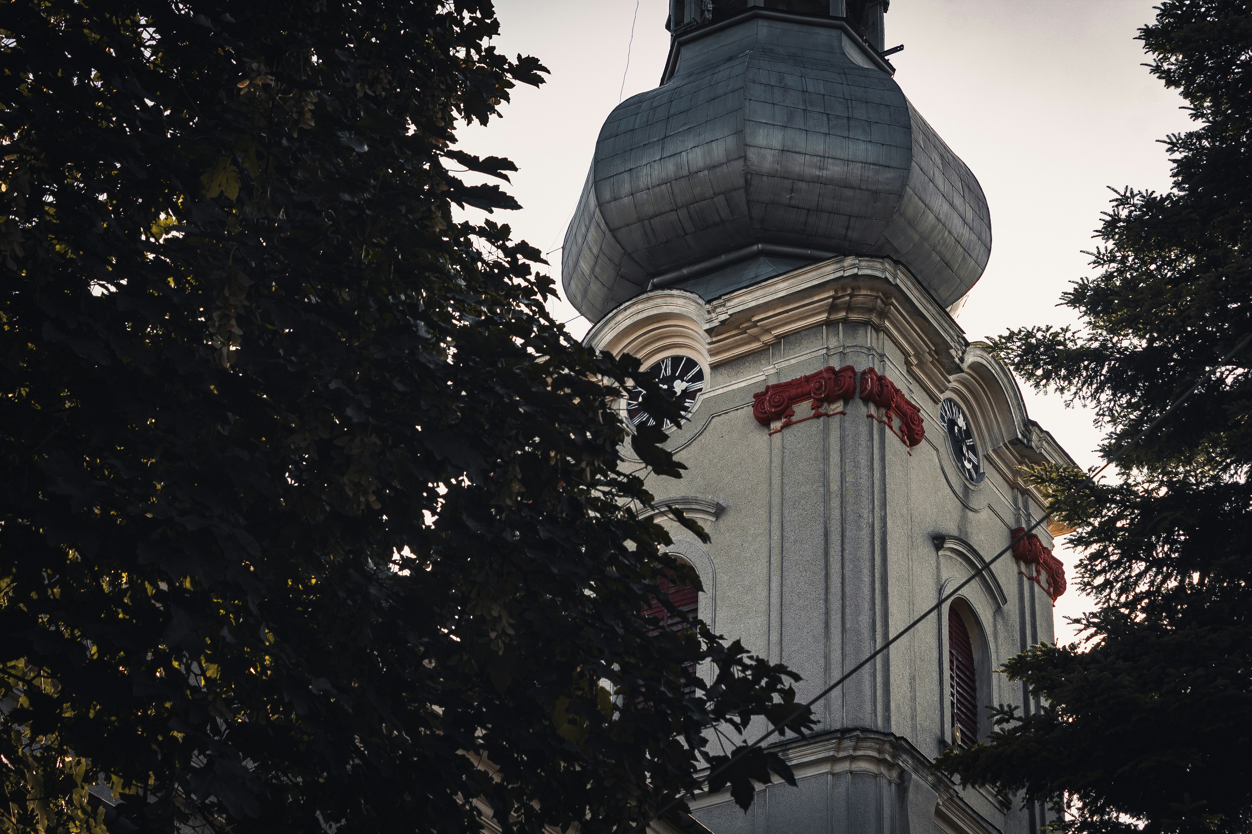 Dusk Over the Spire: A Baroque Clocktower Veiled by Foliage