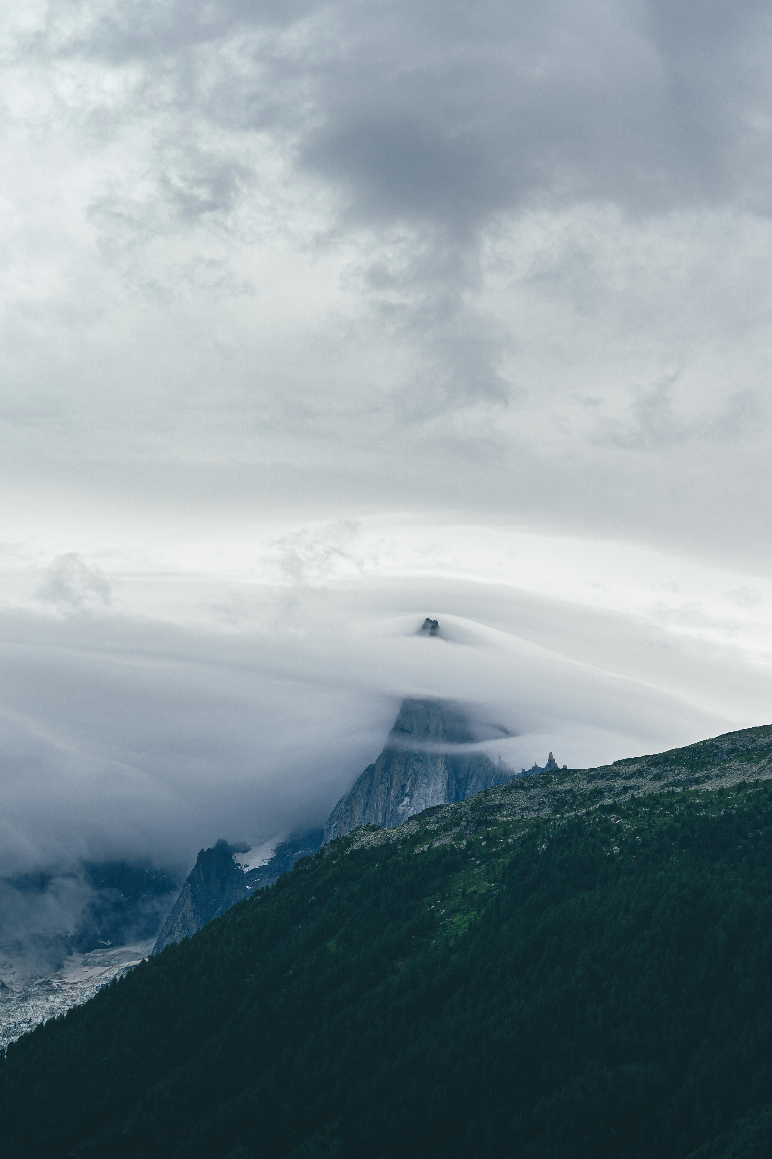 a mountain covered in clouds with a mountain in the background