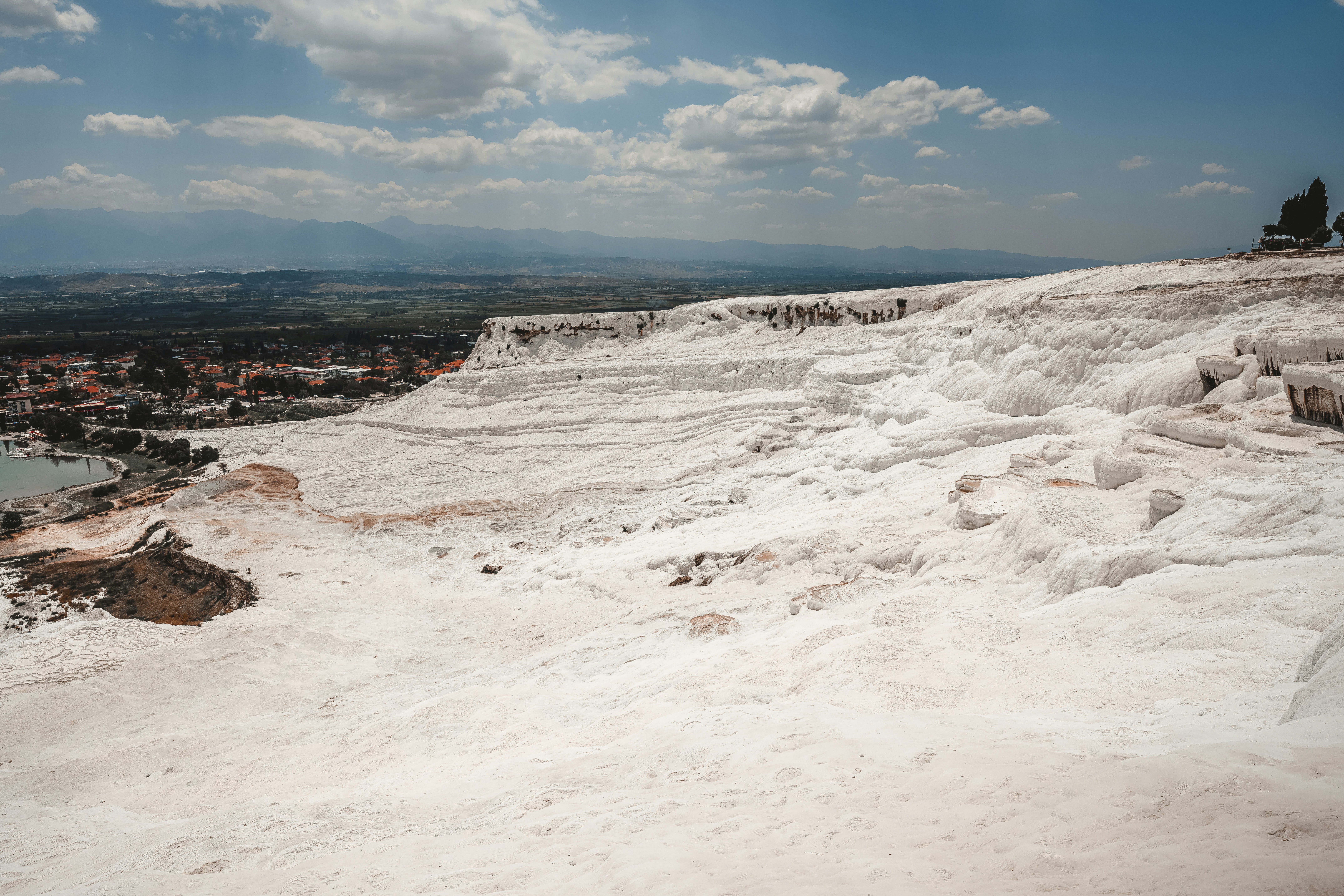 Snow-like terraces stretch towards a distant city under a bright blue sky.