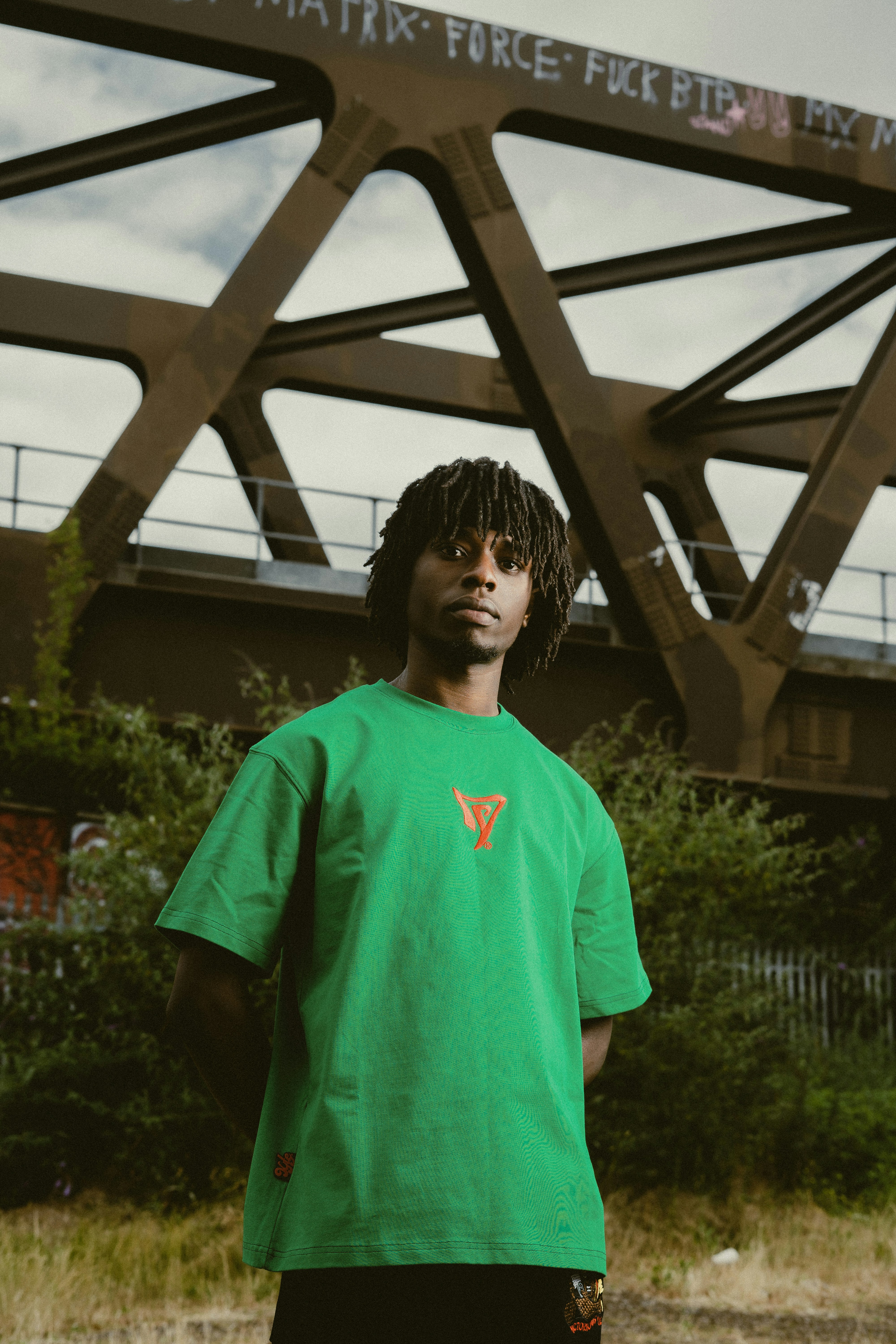 Green Tee, Concrete Arches: Portrait Under A Steel Skyline
