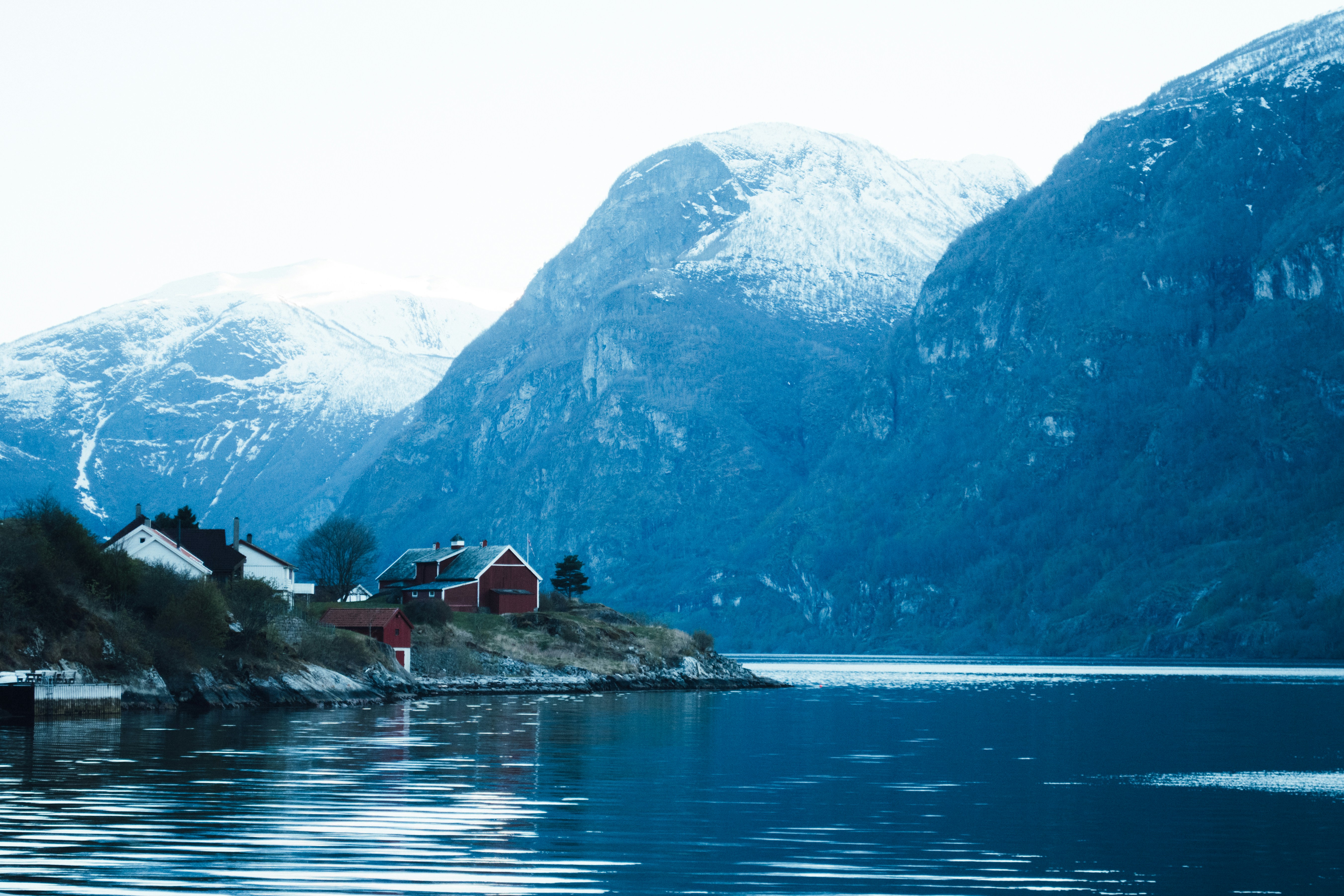 Red-roofed Cottages at Fjord’s Edge Under Snow-Dusted Giants