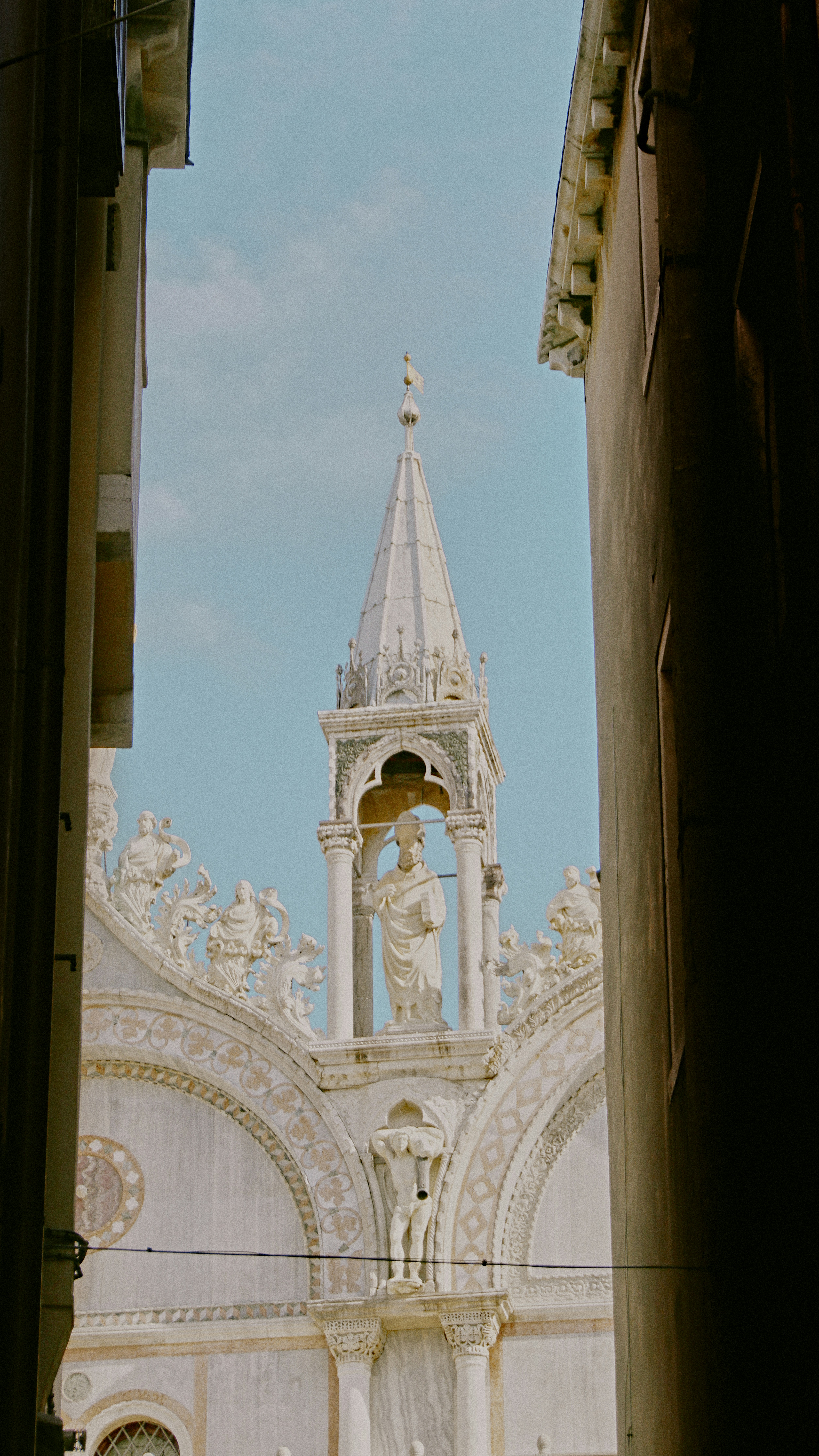 Spire in the Gap: Sunlit Cathedral Crowned Between Narrow Walls